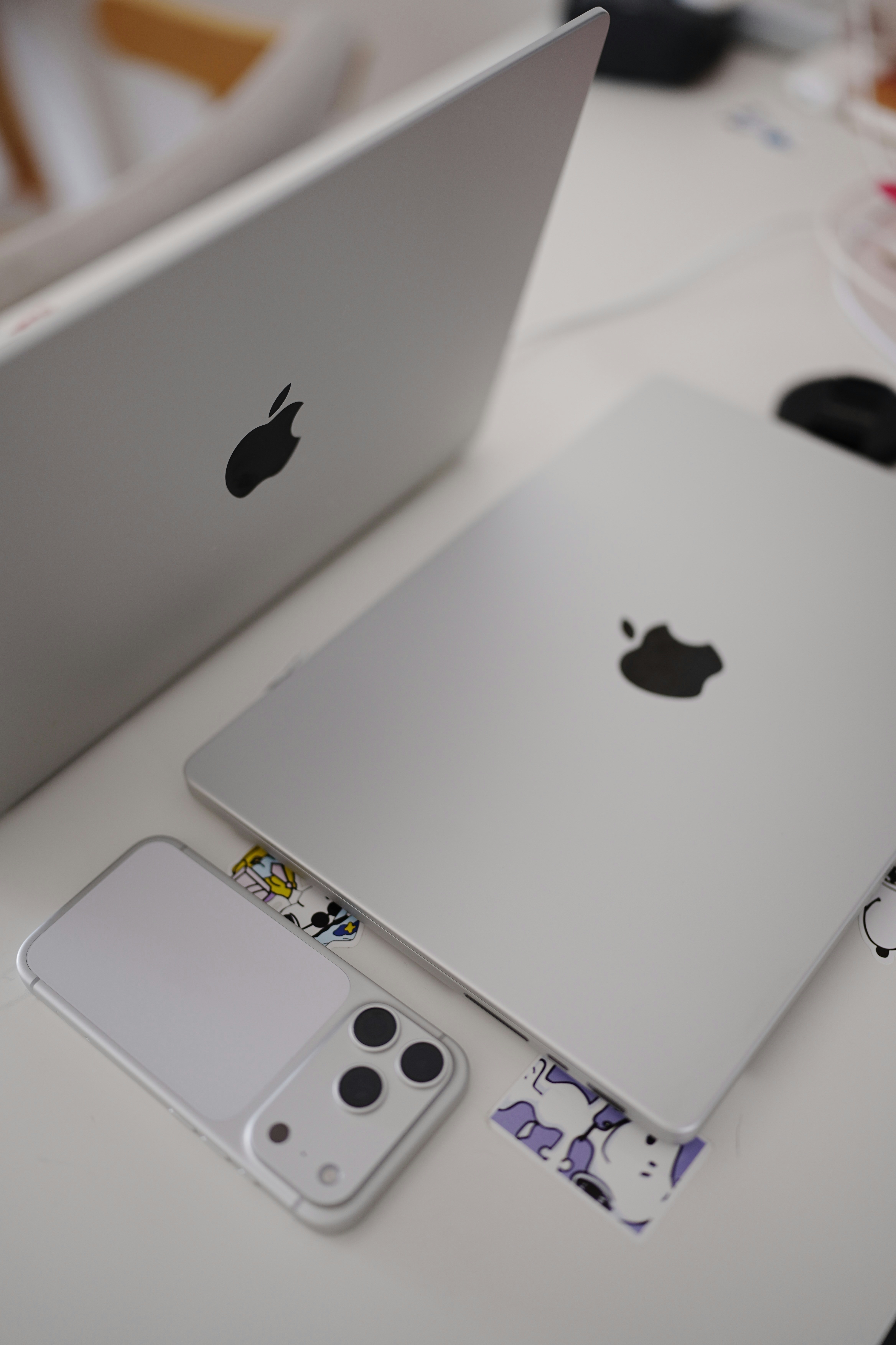 Silvery Apple Ensemble: A Trio of MacBooks and an iPhone on a Marble Surface