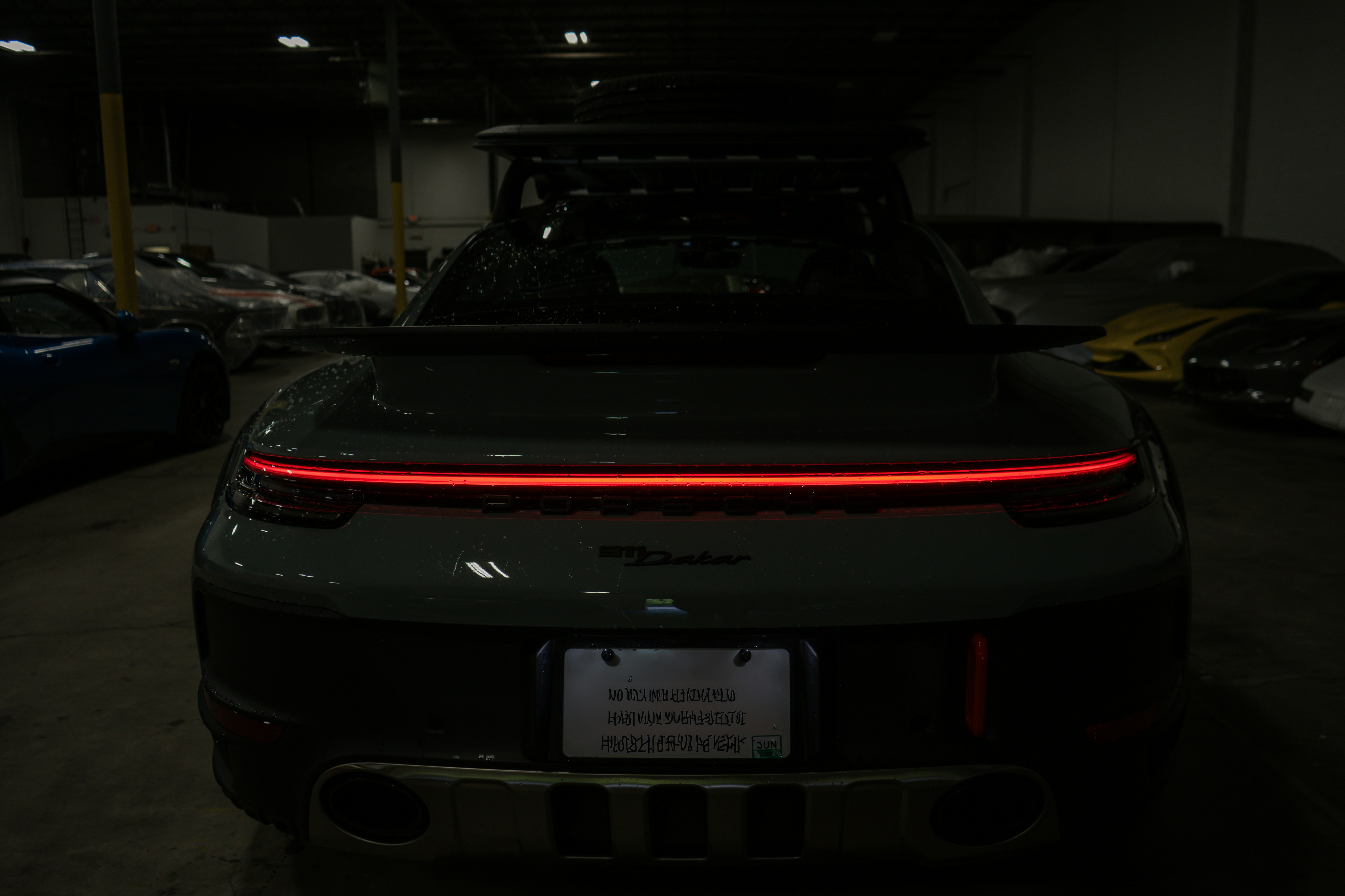 Rear Profile of a Dark Porsche Turbo in a Dim Indoor Parking Garage