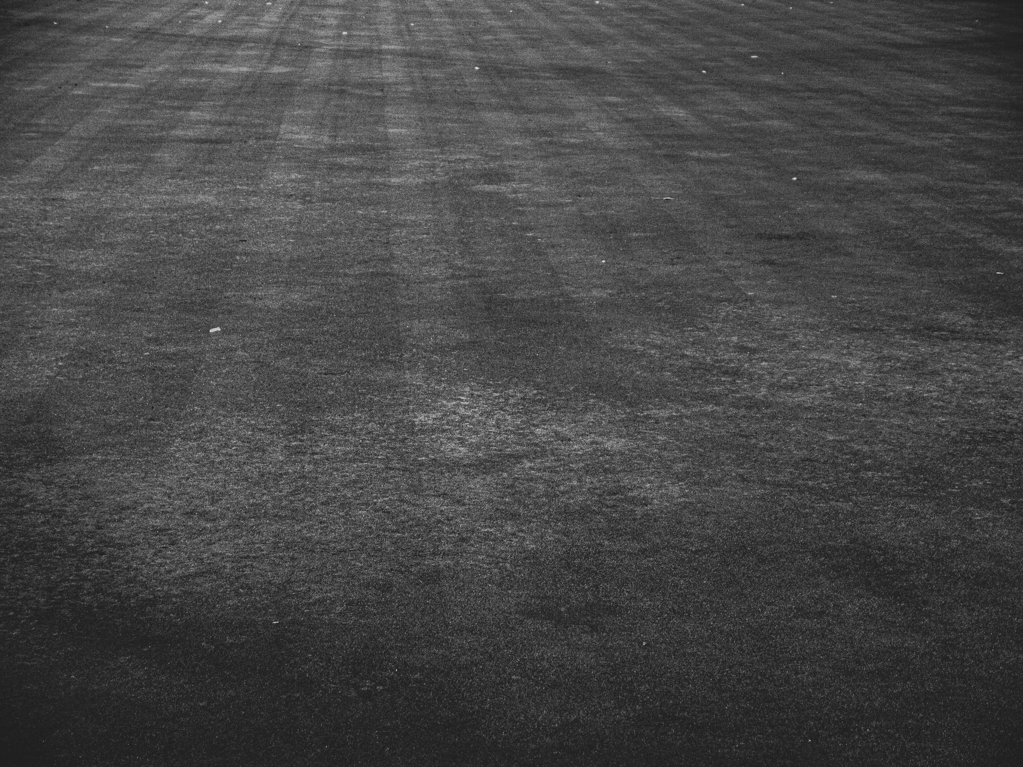 Monochrome textured field with gentle tonal variation and faint radial patterns near the upper edge; minimal subject, emphasizing surface detail and mood. The image appears to be a logo-free, photographic texture capture.