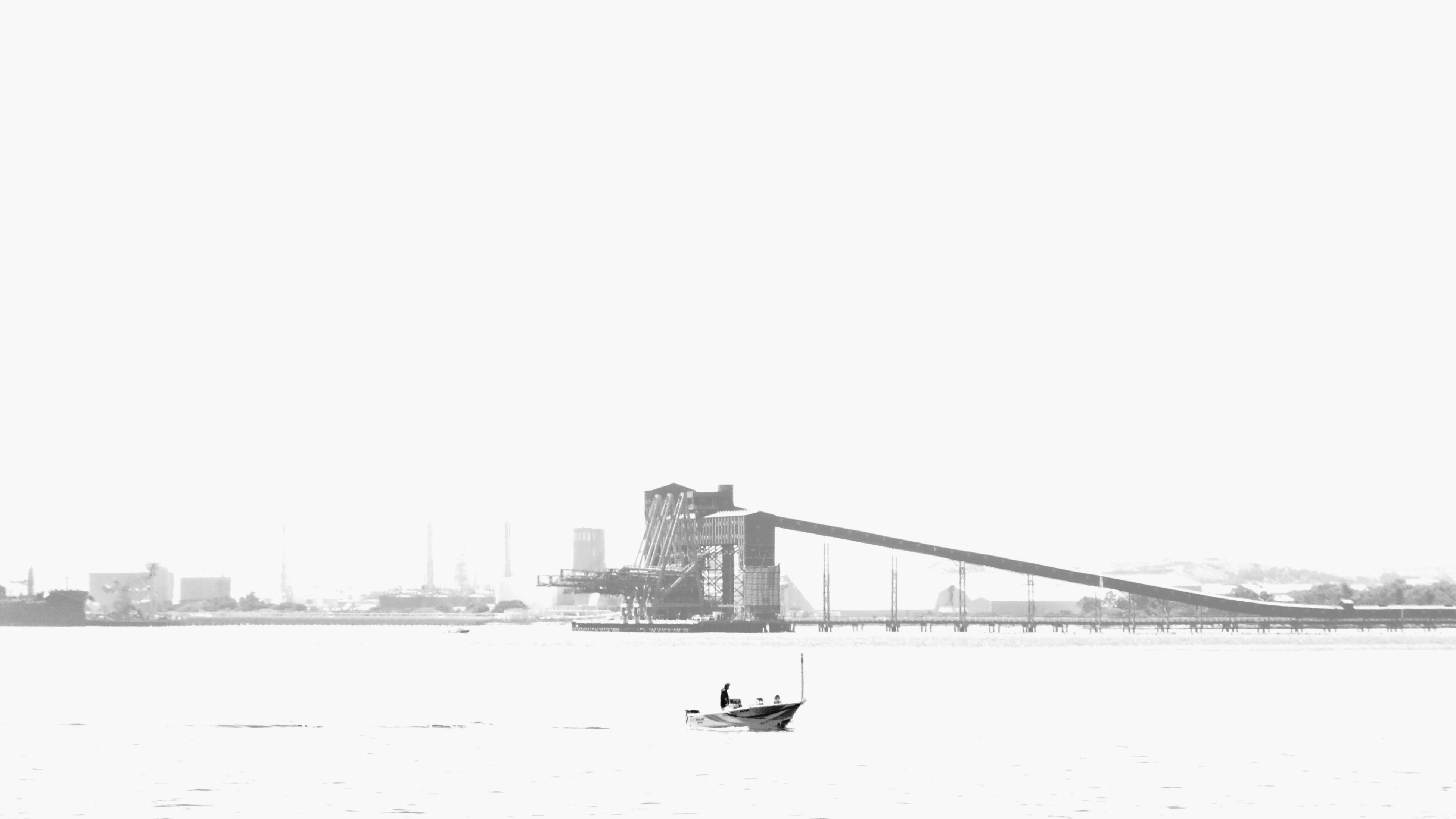 Harbor Silhouette: A lone boat beneath an industrial bridge