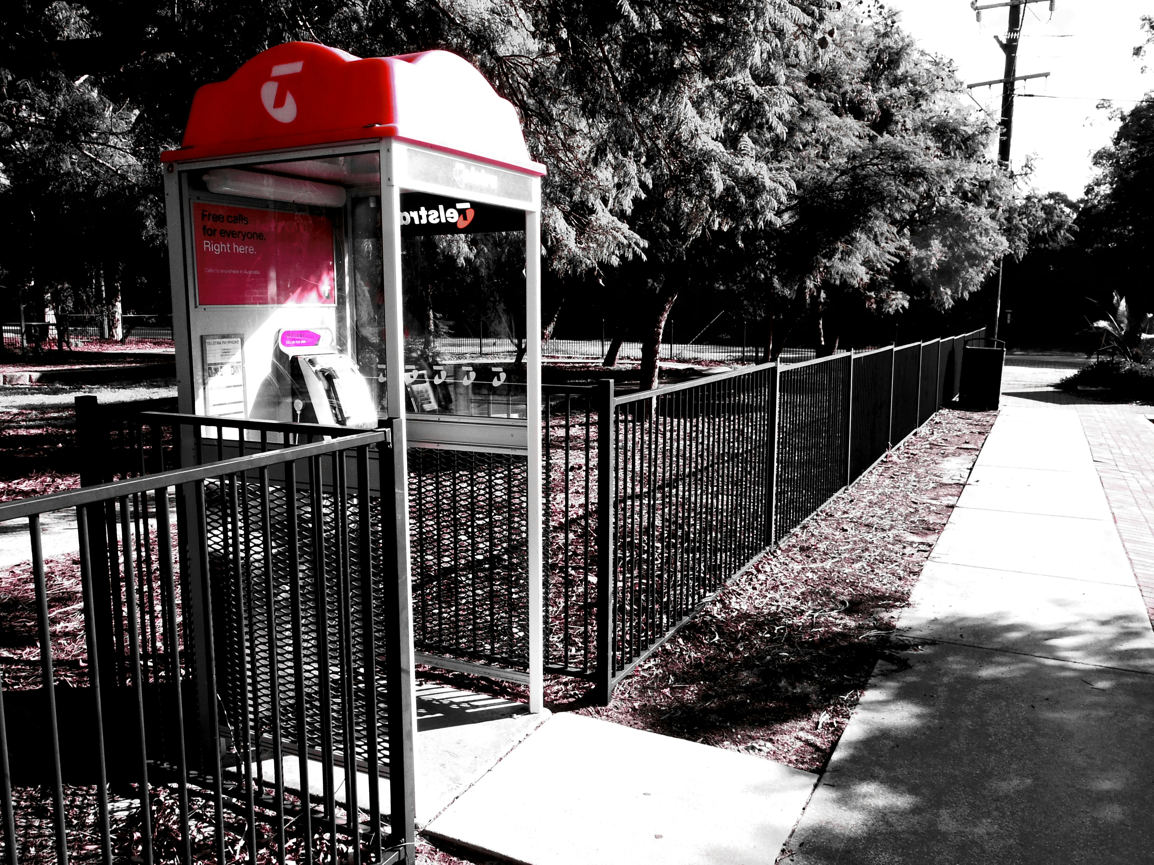 Red Booth, Quiet Street: A Lone Transit Stop in Monochrome