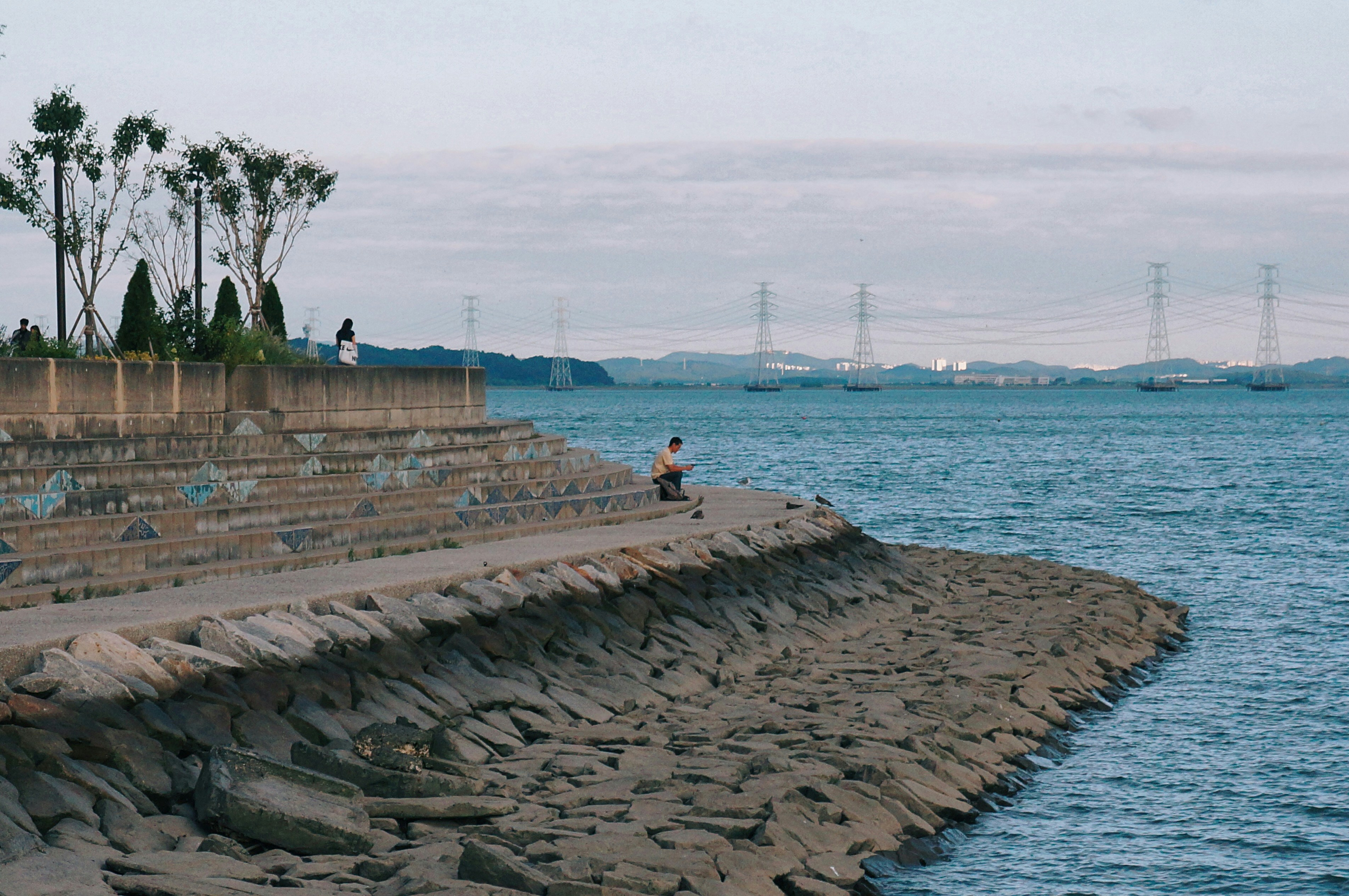 Steps to the Sea: A Lone Angler on a Rocky Pier