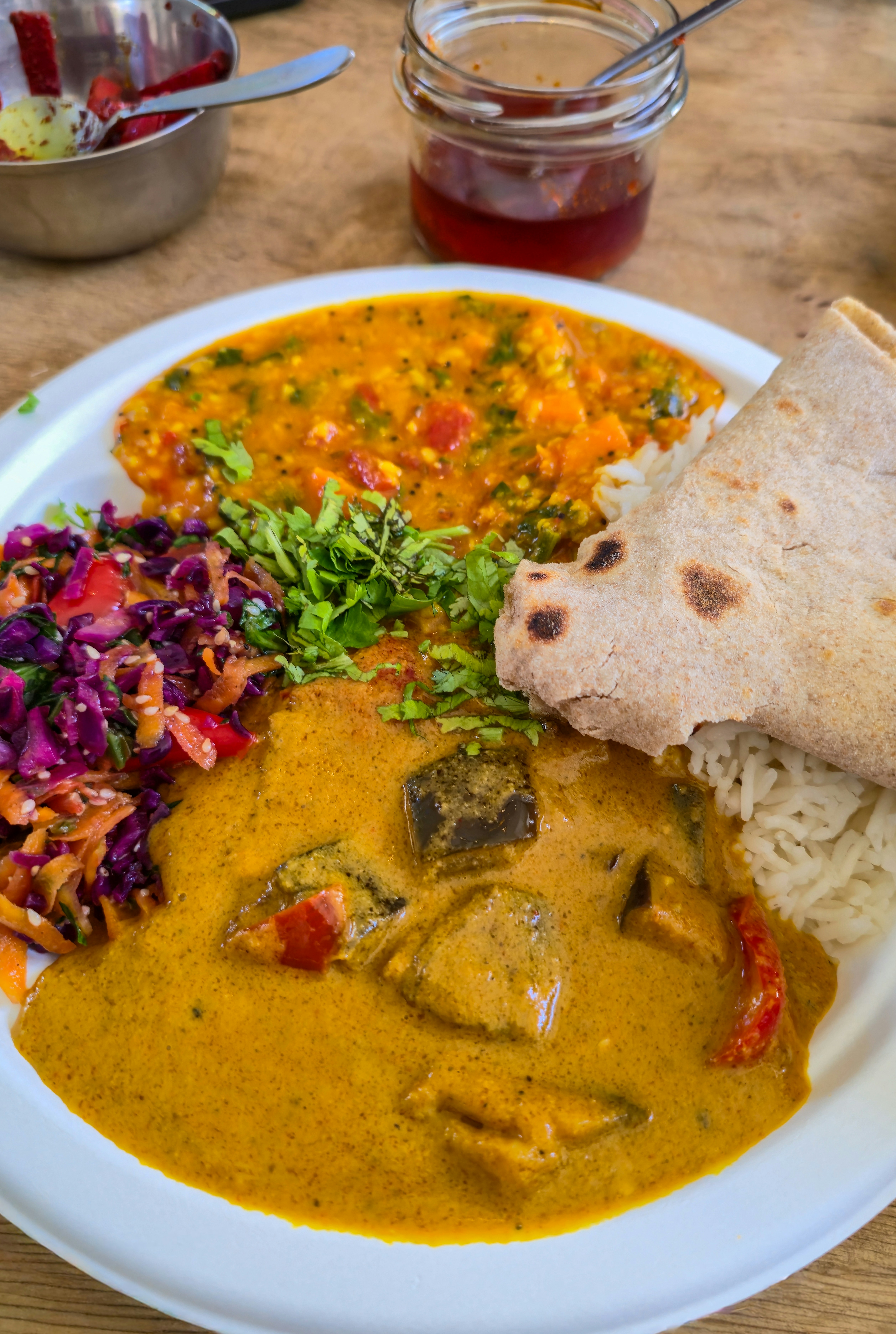 An Indian thali plate filled with vegetable curry, red cabbage salad, a roti, lentil dal curry, and rice