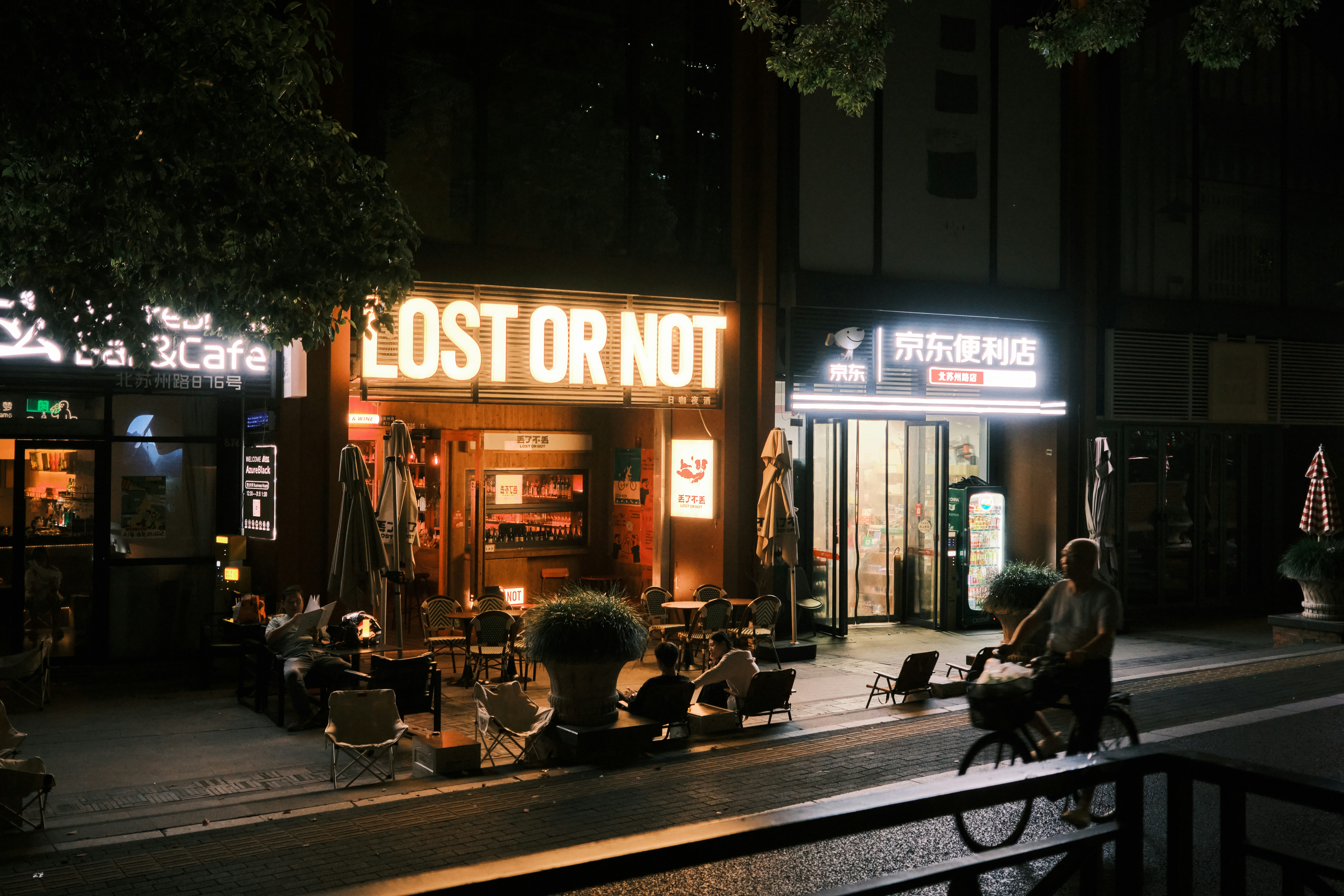 Neon glow and evening chatter outside a tucked‑in cafe corridor