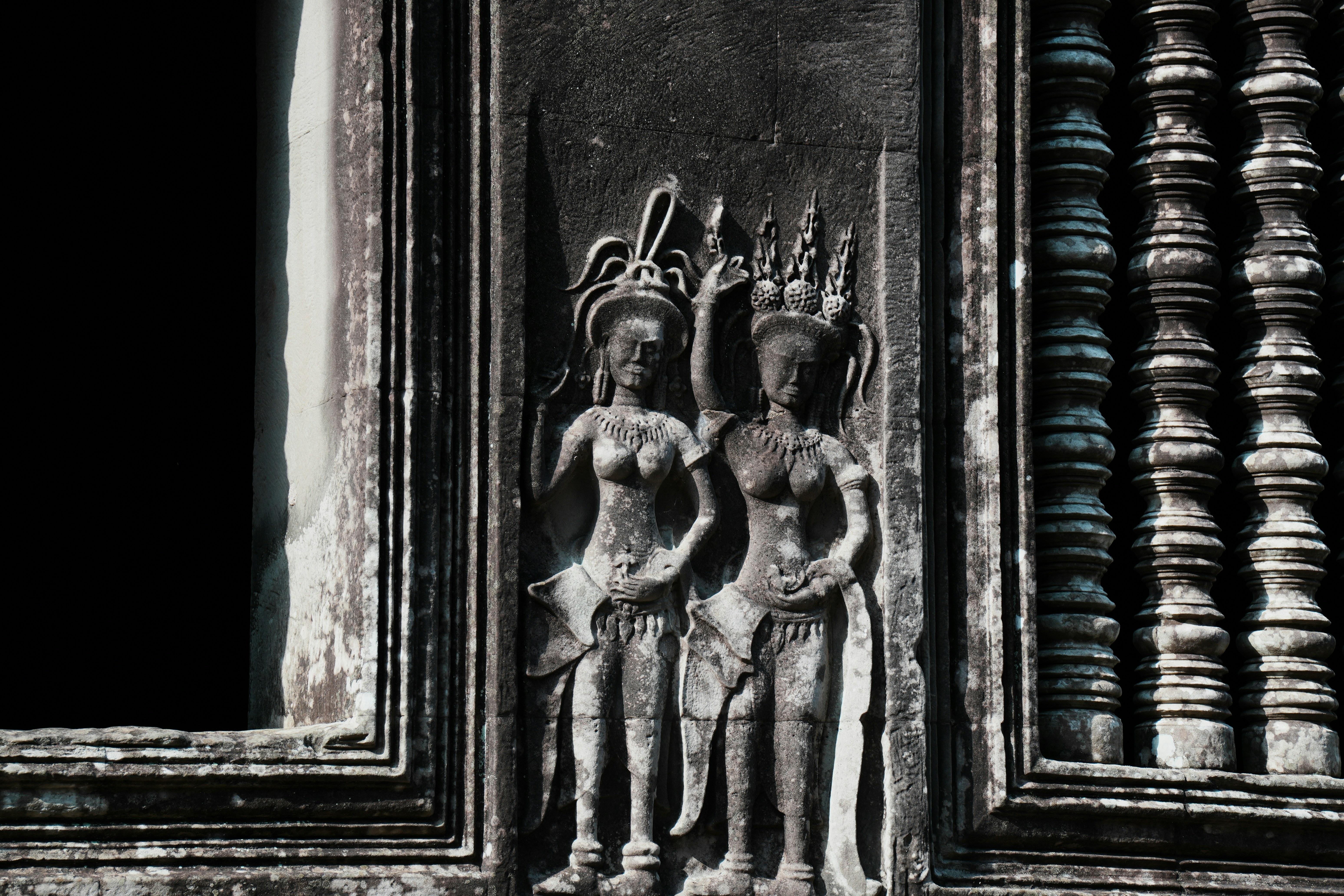 Stone Guardians at Dusk: Carved Figures Framing a Window