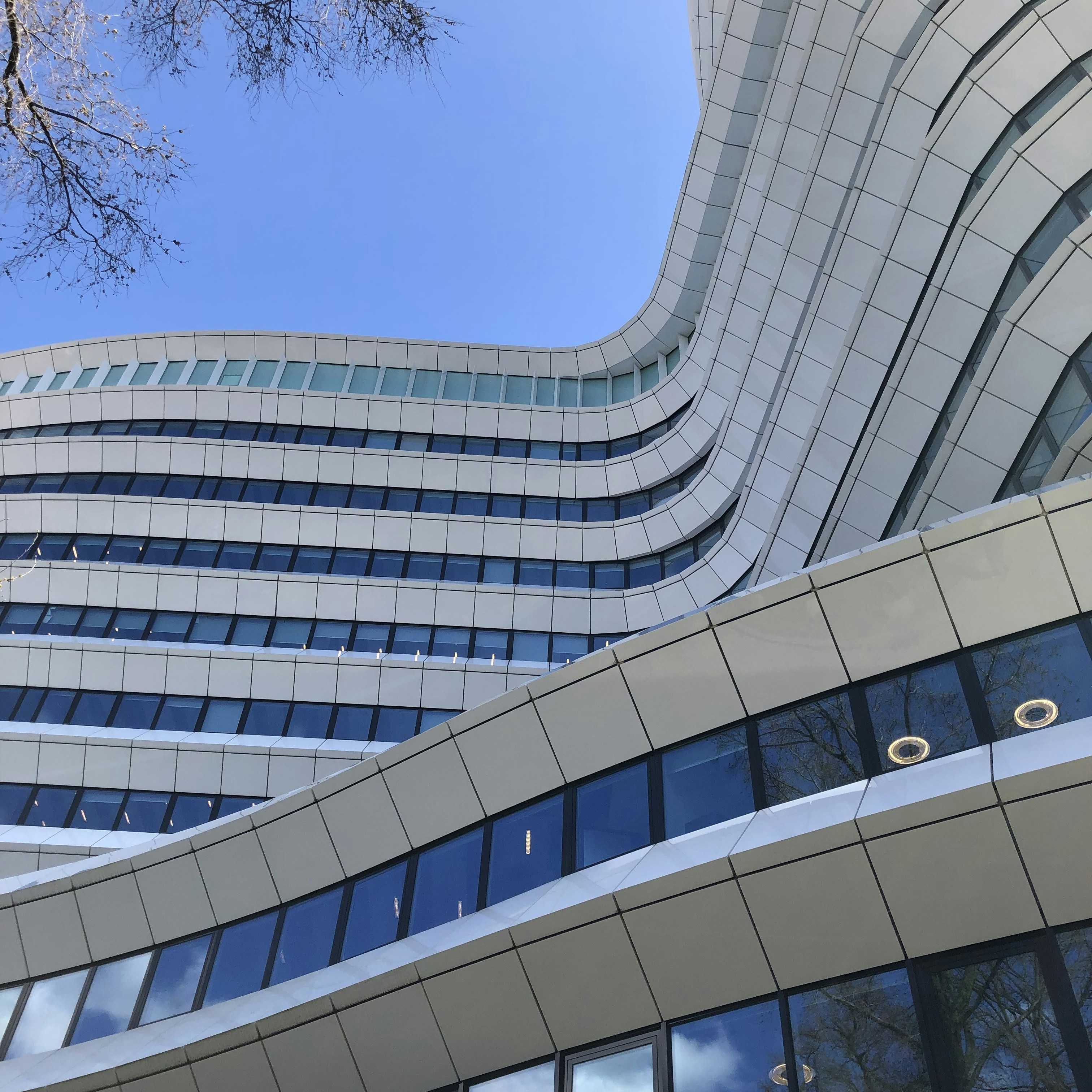 Curved Glass Facade: Modern Architecture Rising in Blue Sky