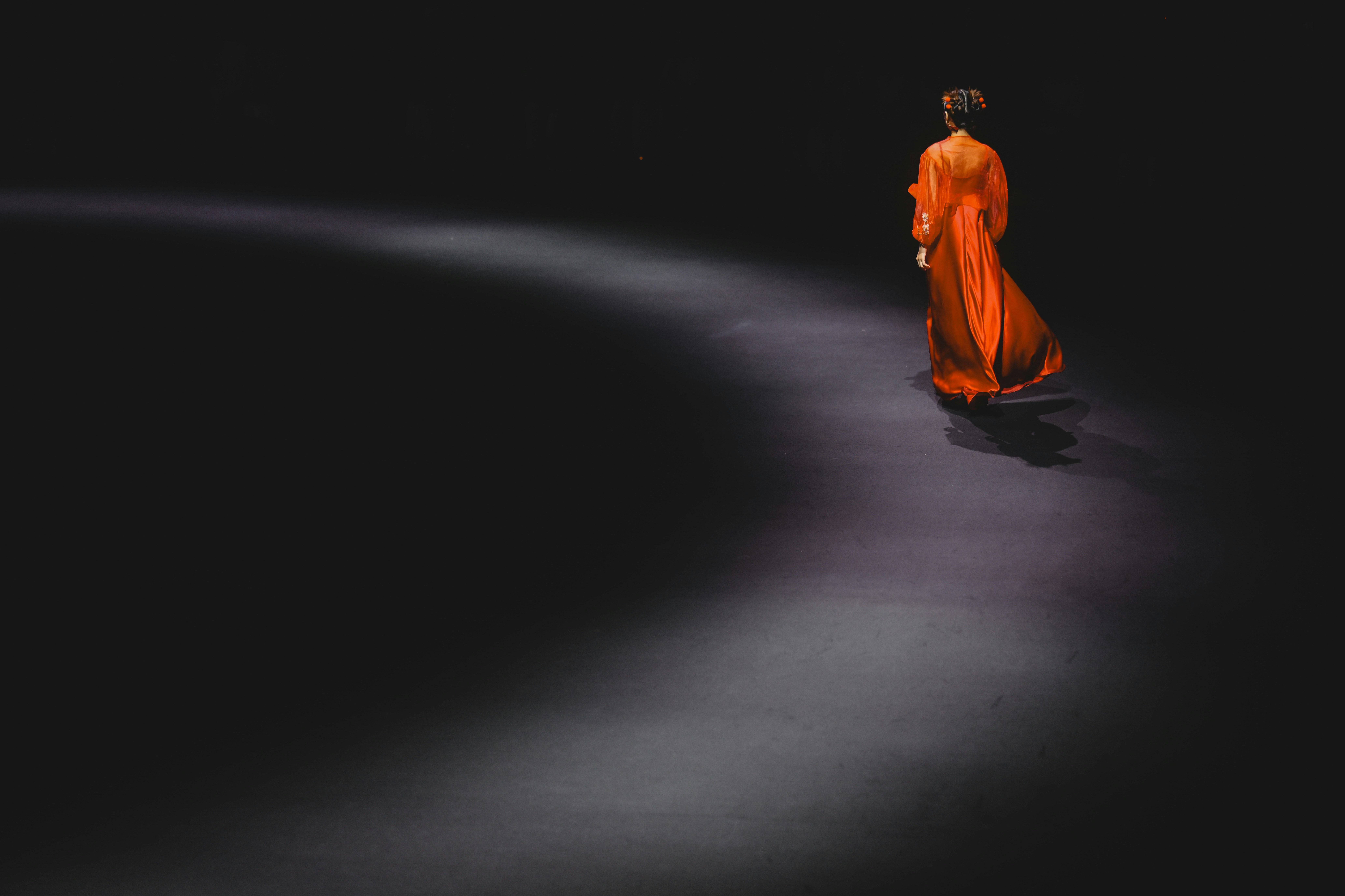 Crimson figure in a spotlighted arc
