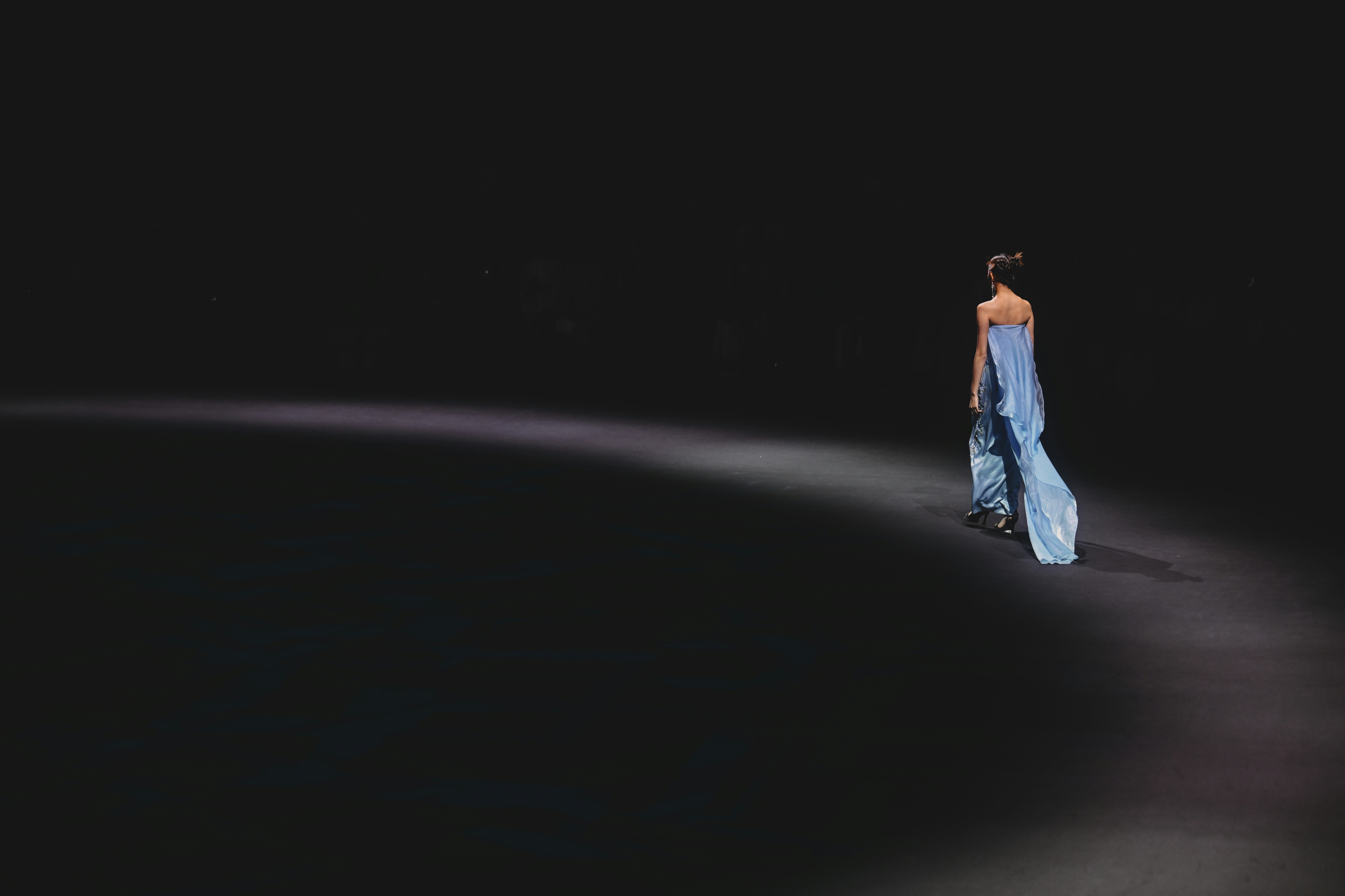 Spotlight on Elegance: A Figure in Blue in an Endless Dark