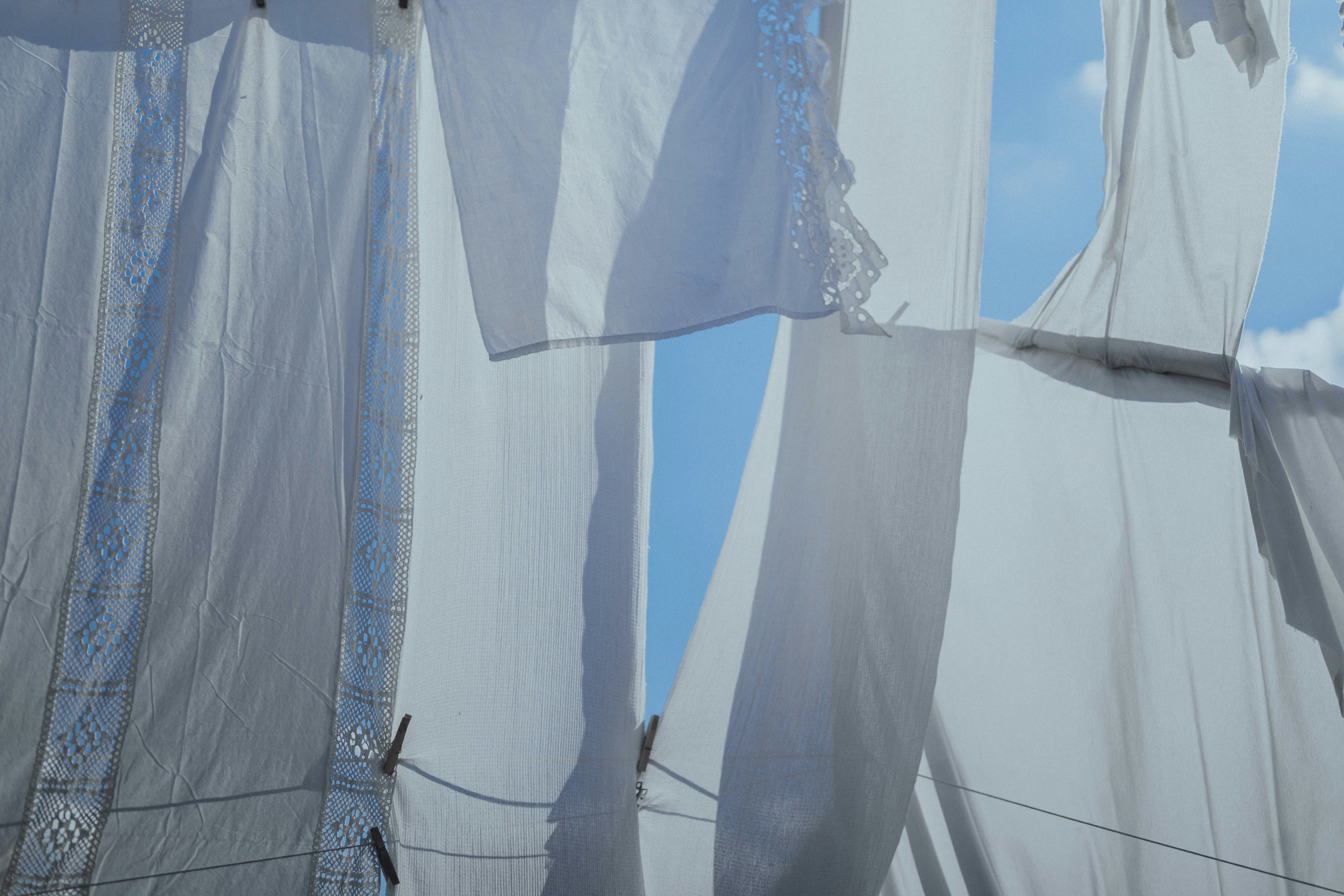 Floating linen: sunlight threads through wind-tossed fabrics against a bright blue sky