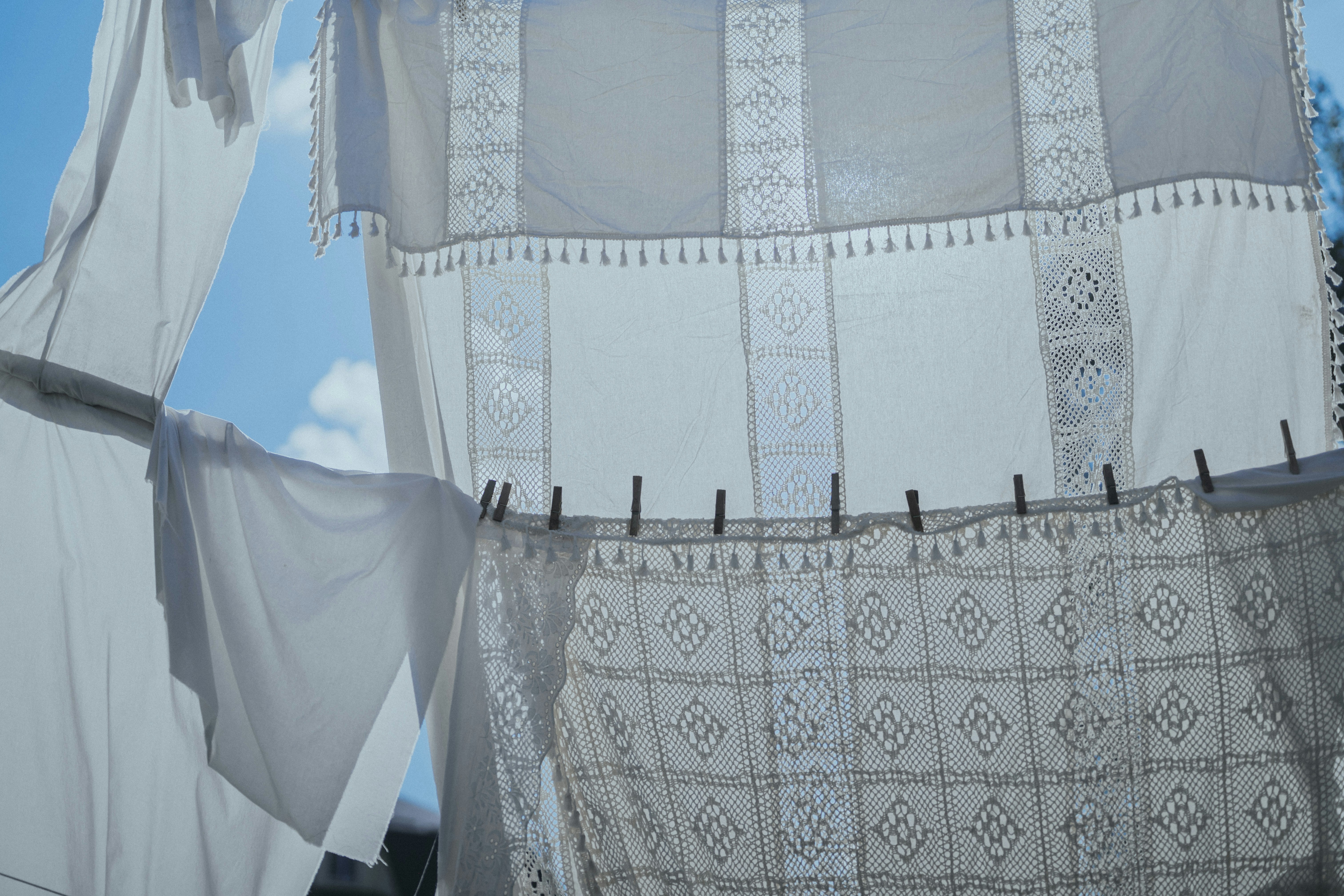 Loomed Grace: Sunlit White Lace Drapes Against a Bright Sky