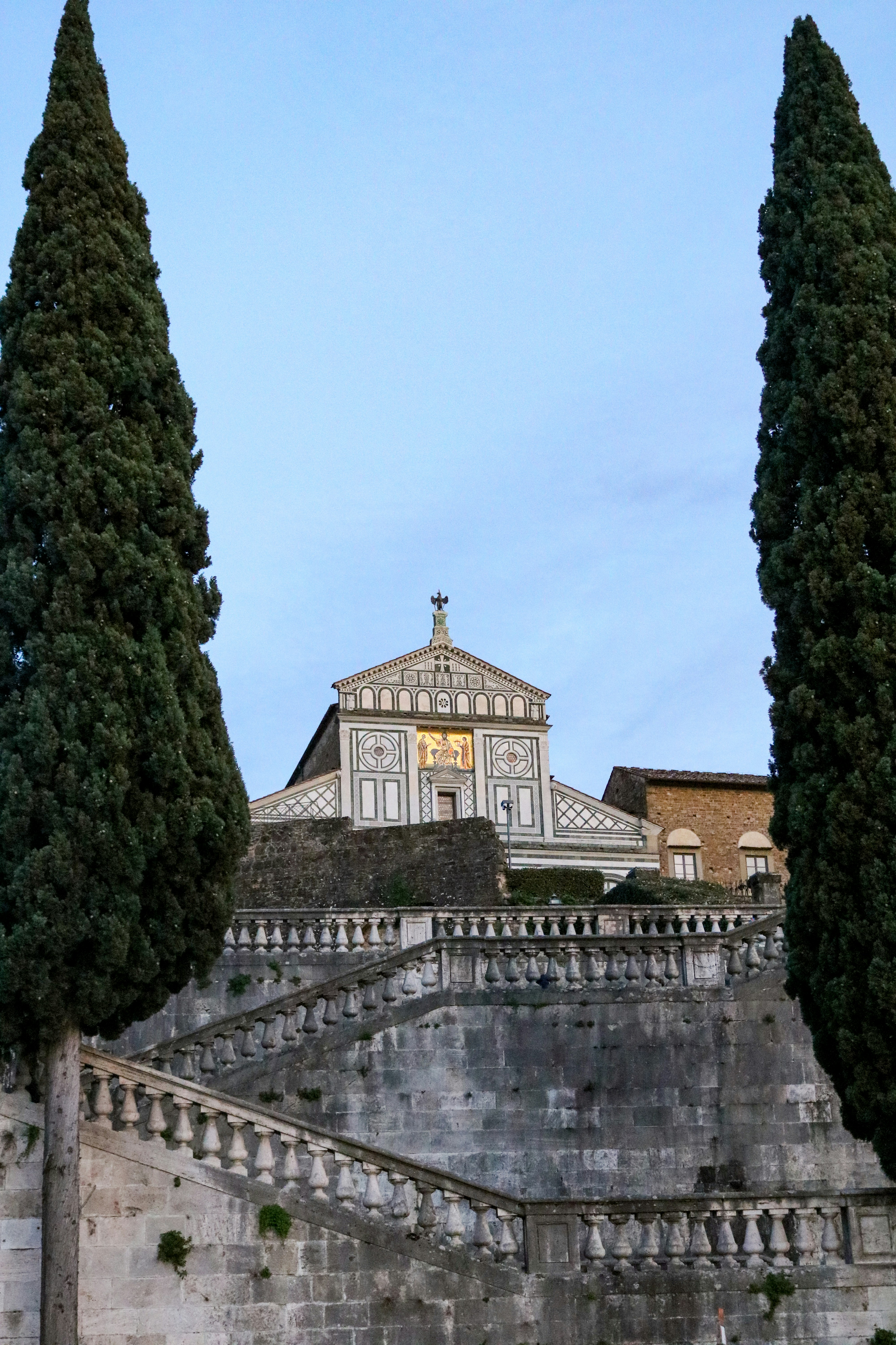 Terraced ascent toward a gem-stone chapel framed by towering cypress sentinels