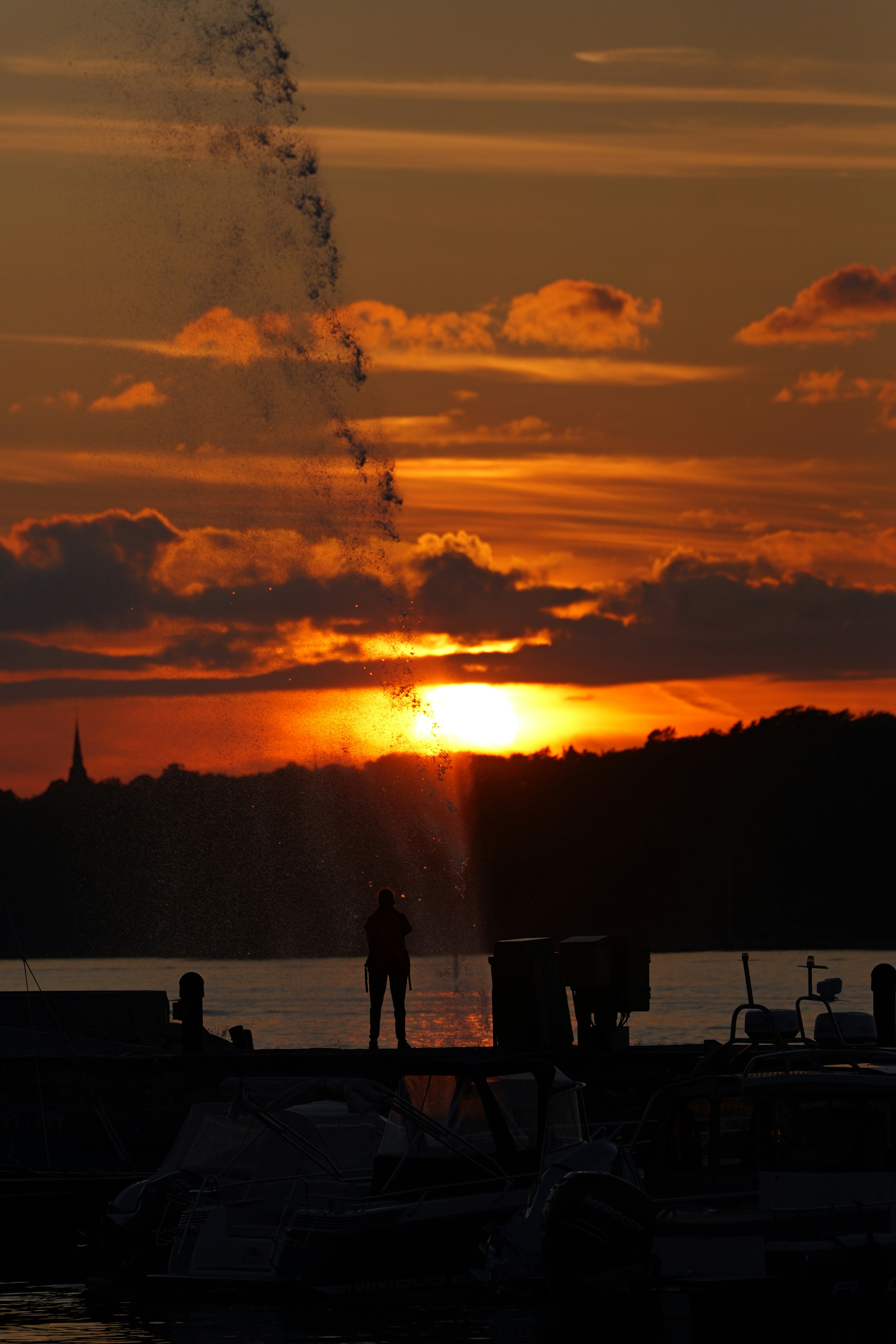 Silhouette at Sunset: A Waterfront Figure Against a Fiery Horizon