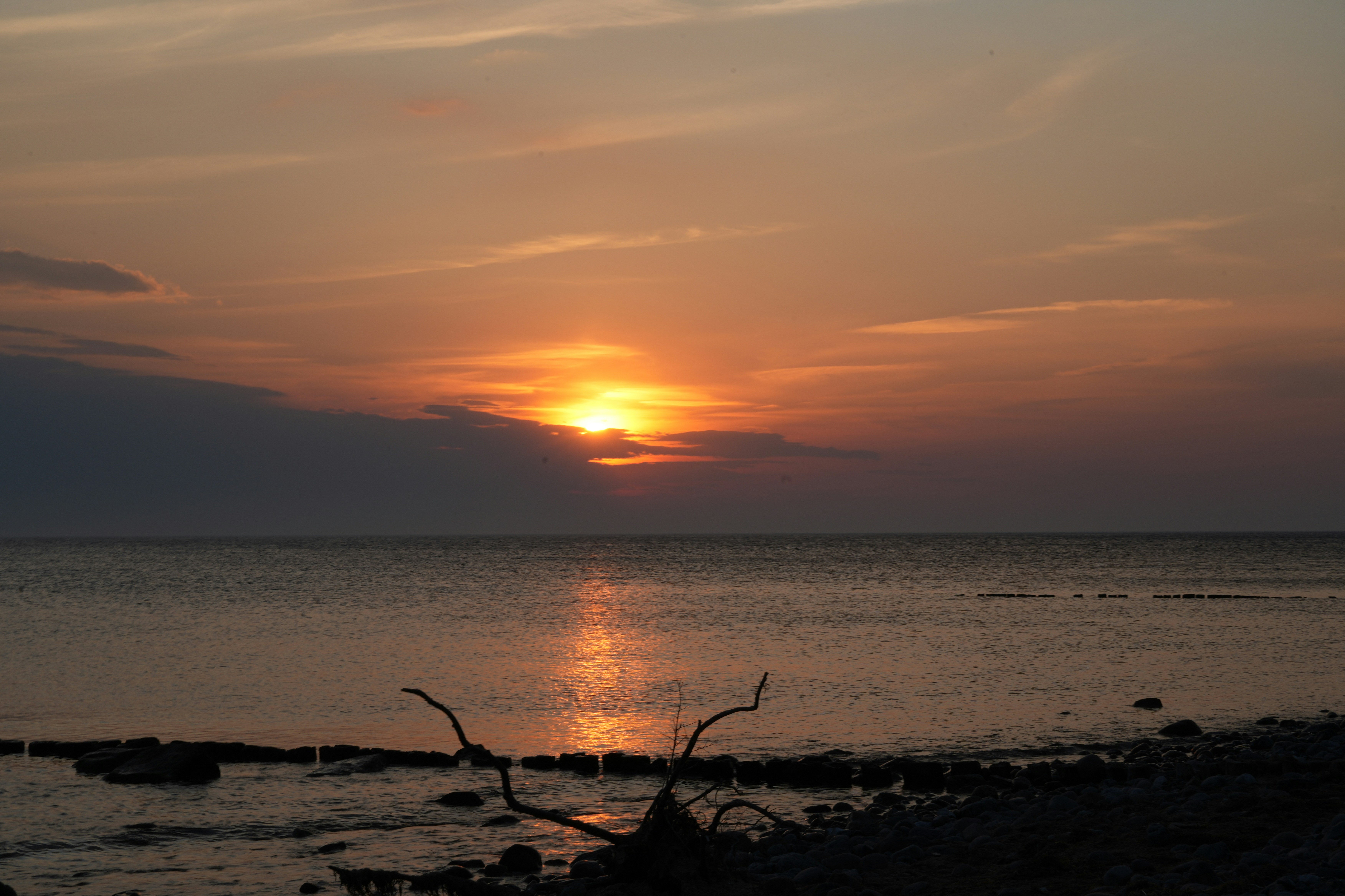 Sunset on a Quiet Shore: Distant Glow Across Calm Waters
