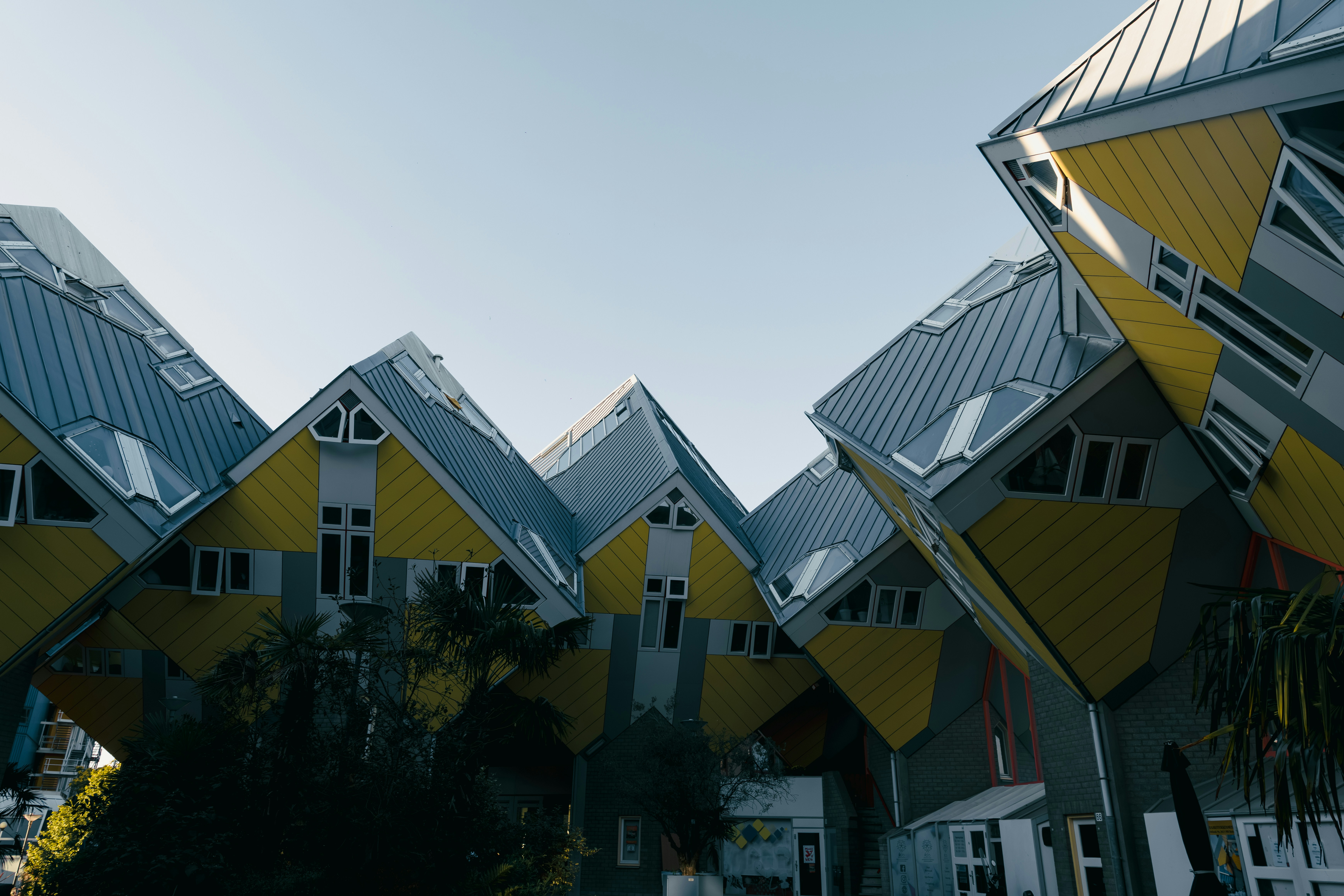 The yellow and grey Cube Houses in Rotterdam under a clear blue sky