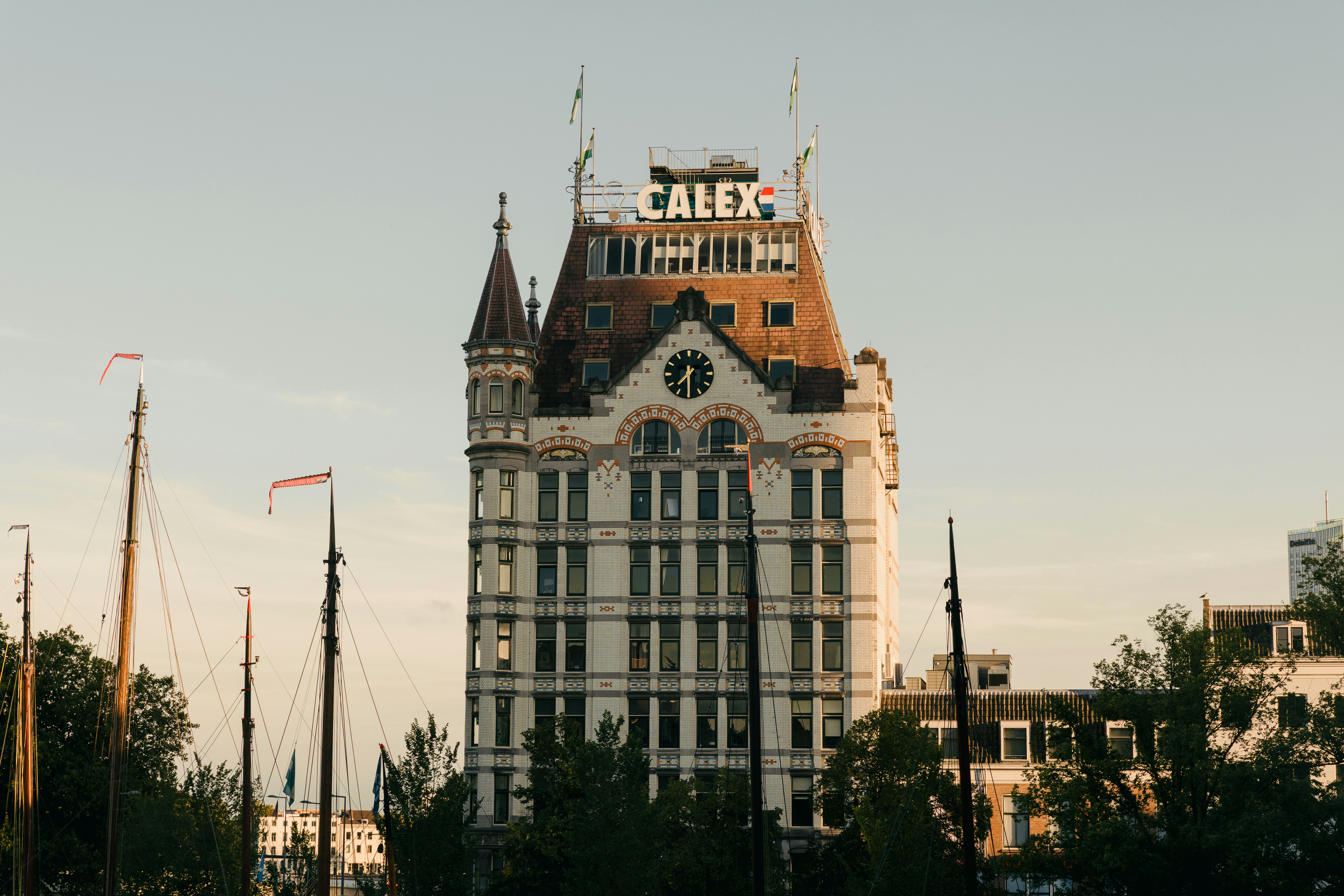The Calex building with a clock tower behind tall ship masts at golden hour