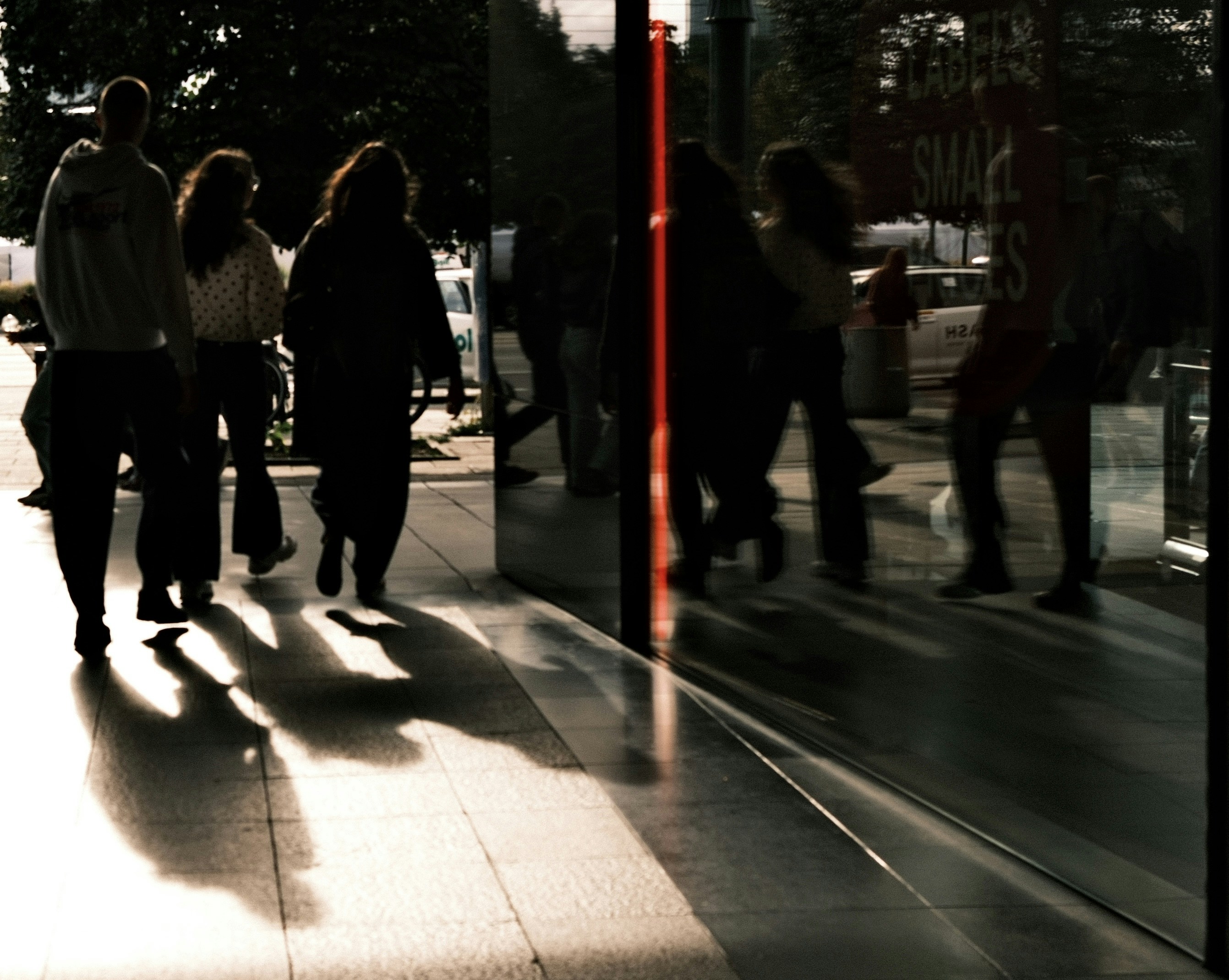 Shadows at the Threshold: Pedestrian silhouettes against storefront glass