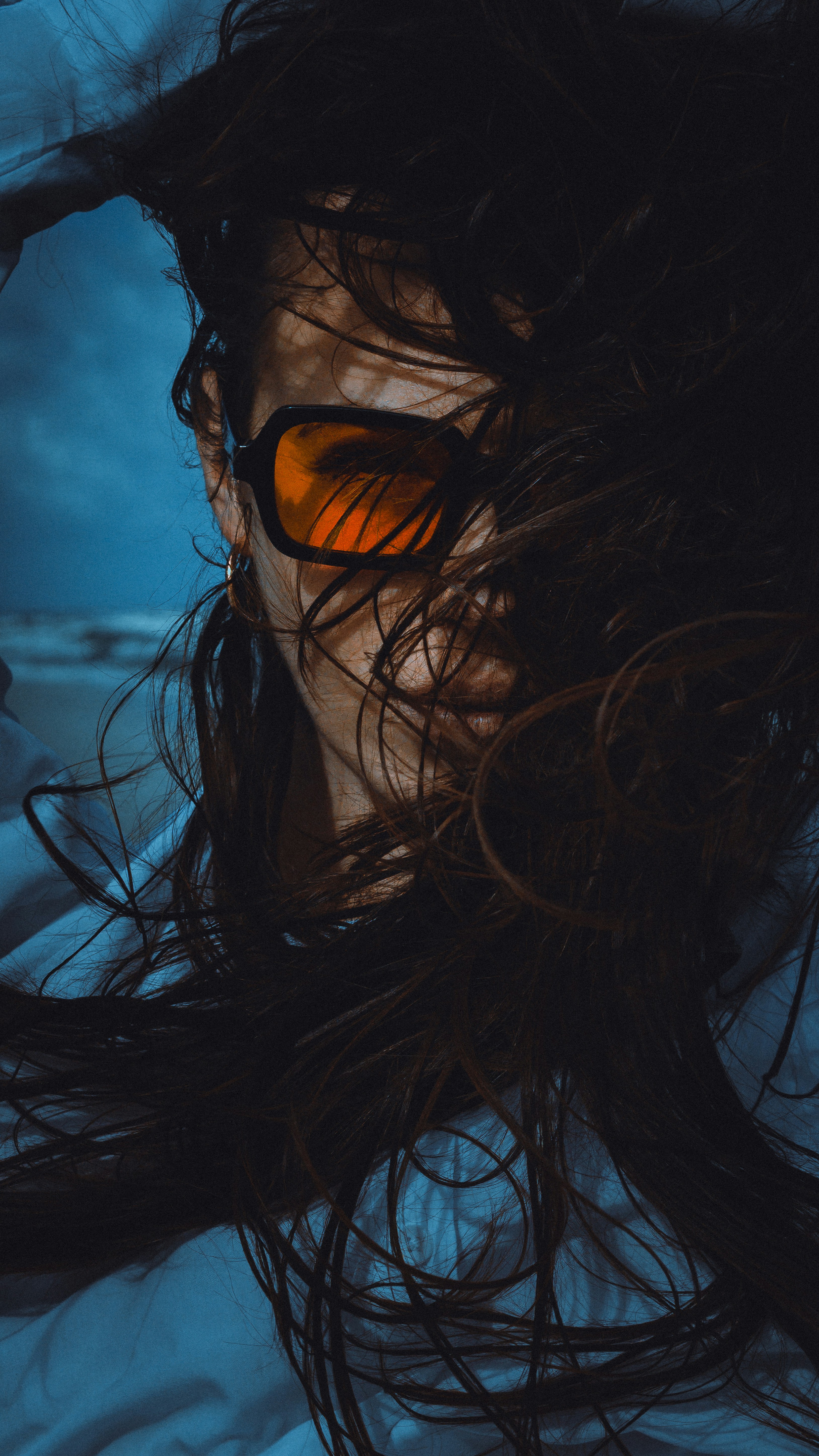 Orange-moggled Gaze: Sunglasses Slice Through Wind on a Coastal Portrait