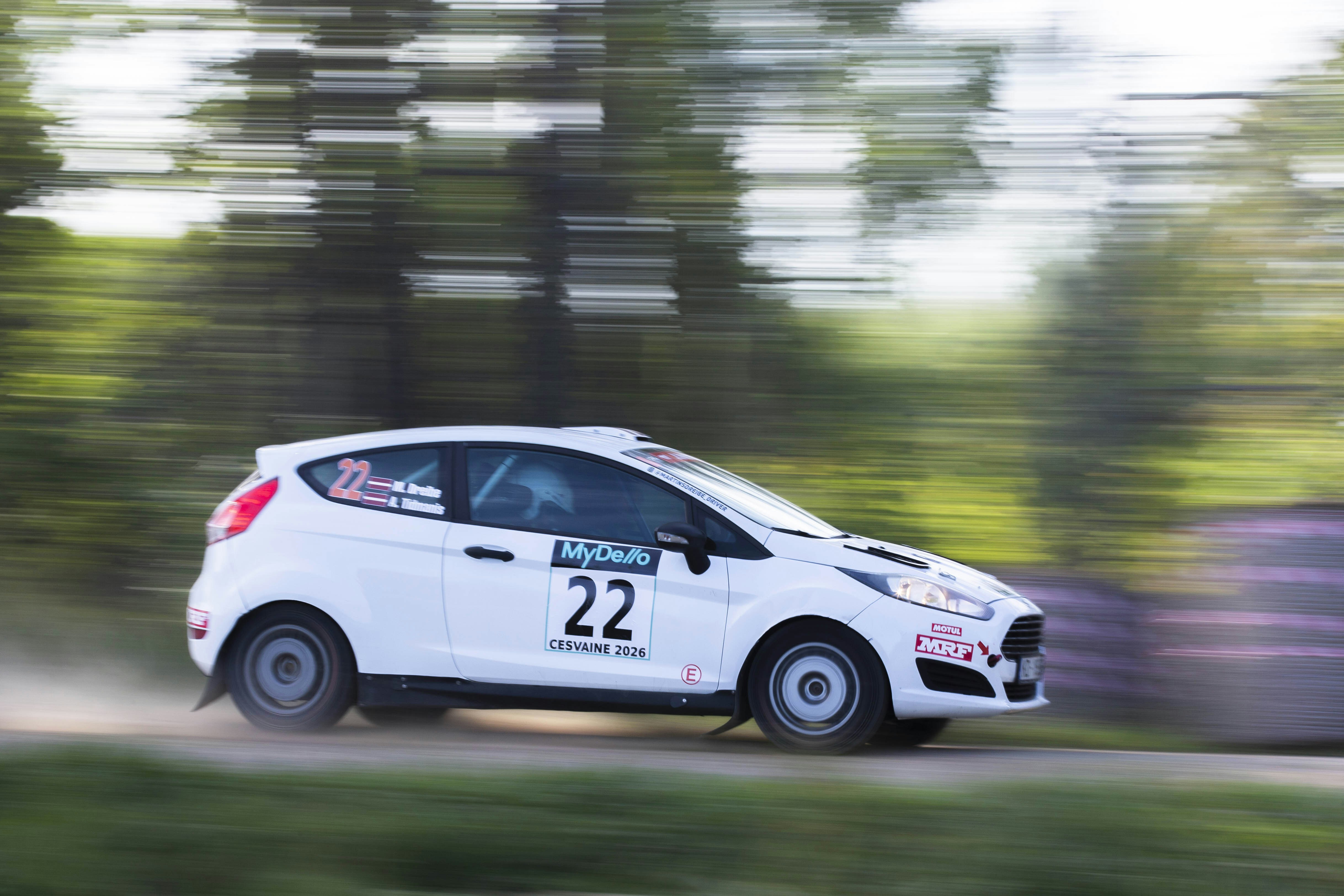White rally hatchback in motion blur on a dirt track