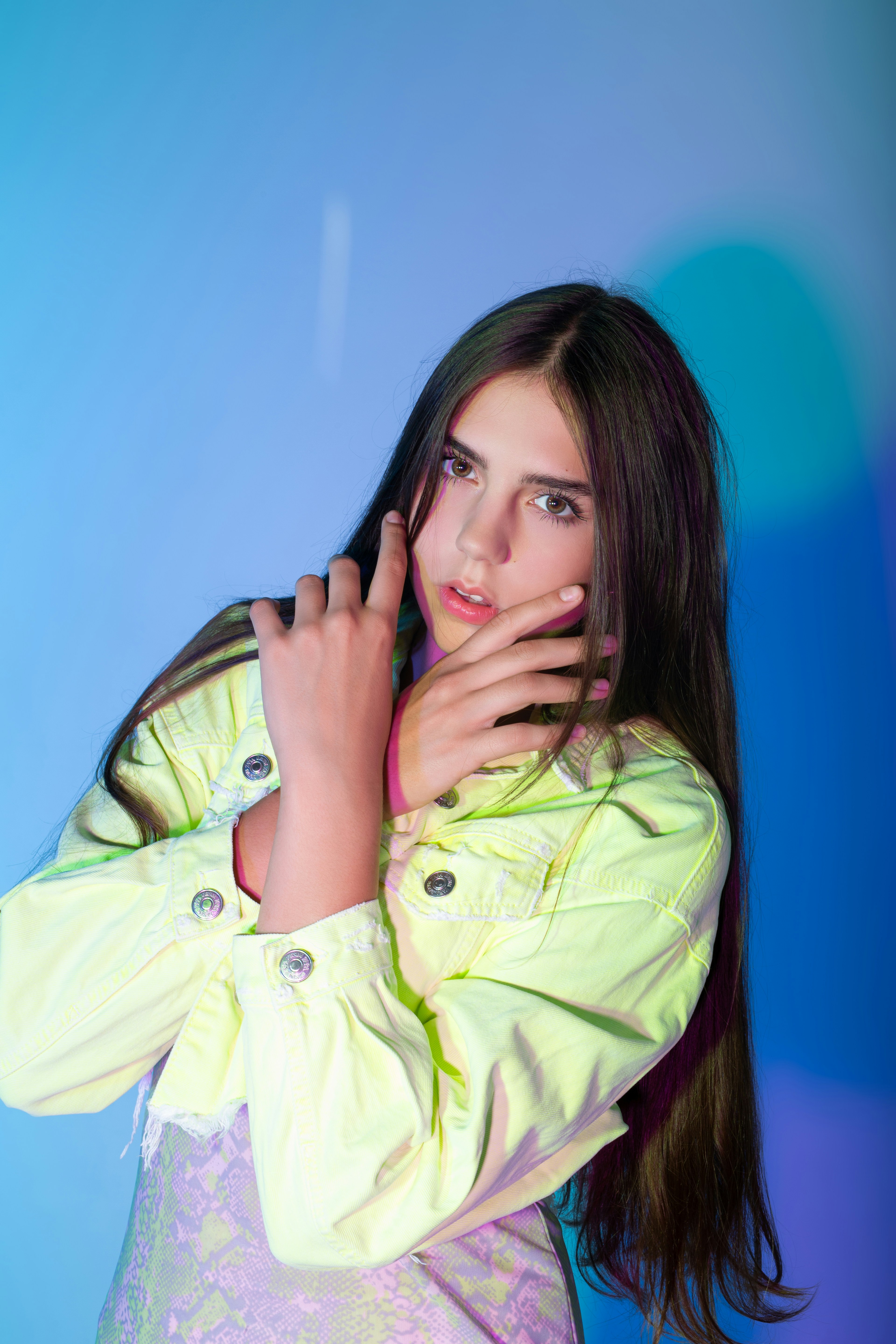 Neon-lit portrait of a young woman in a lime jacket awaiting a moment of expression