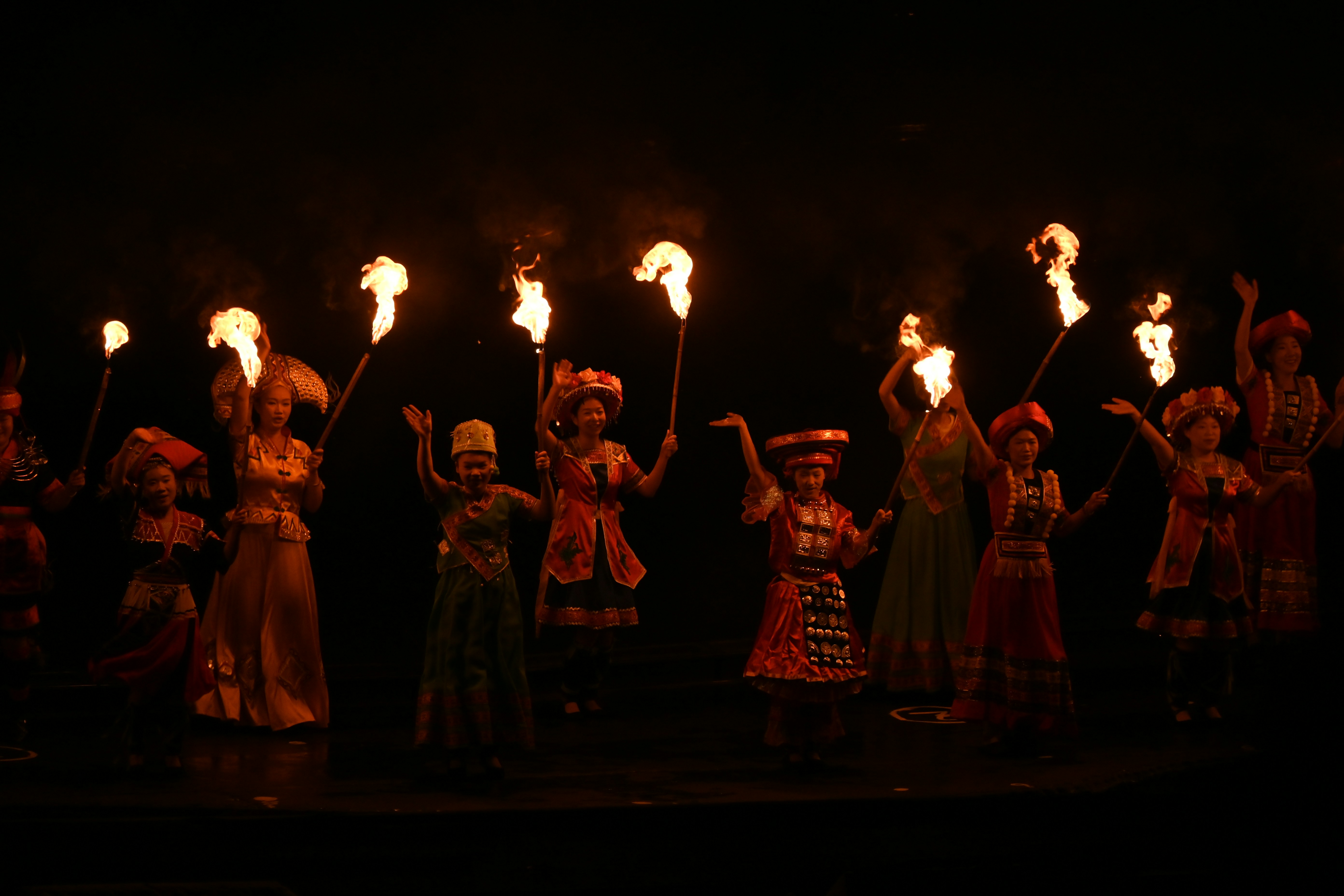 Flame-danced silhouettes: performers lift torches in a midnight parade