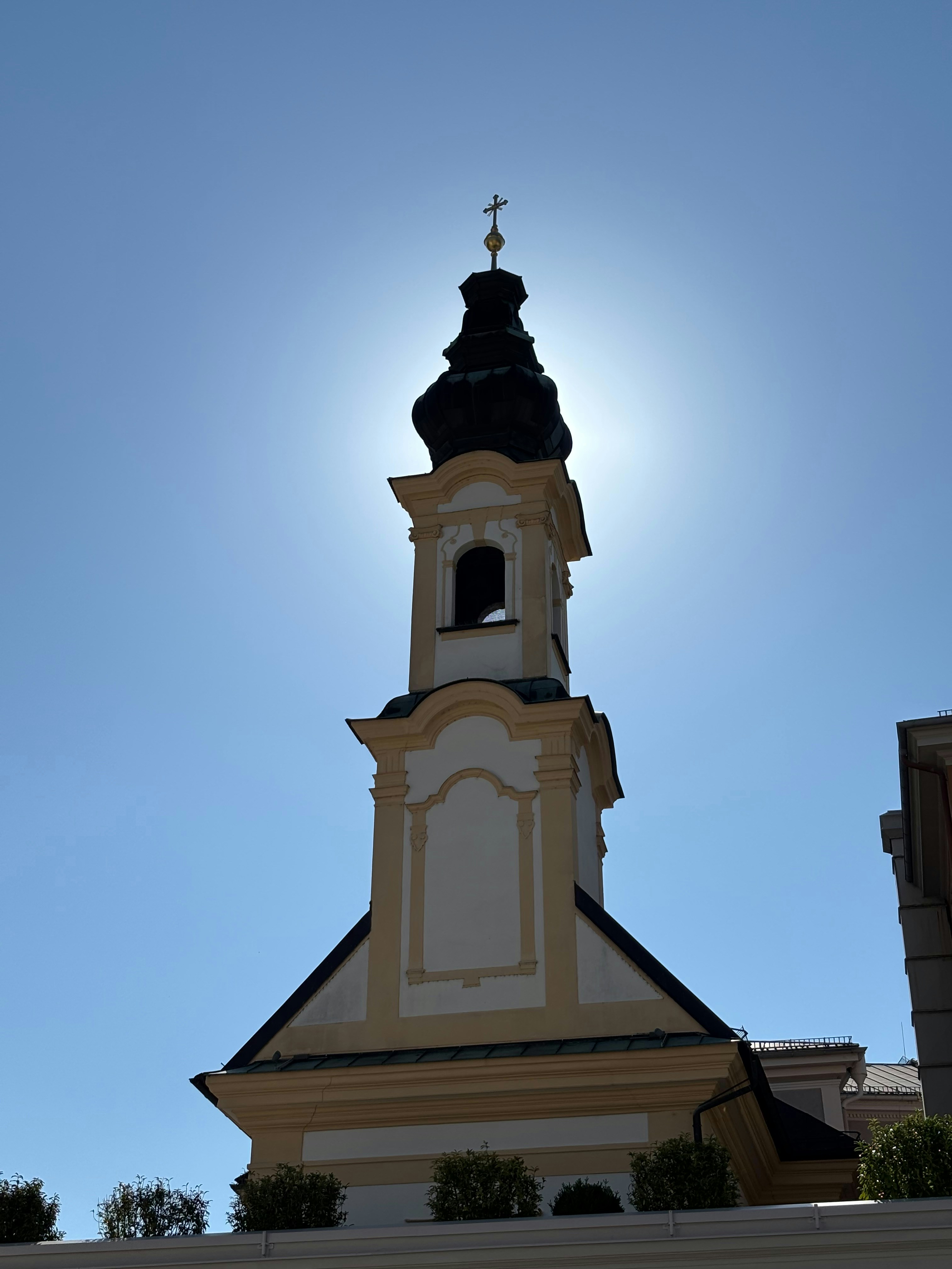 Sunlit Spire: Backlit Church Tower Reaching Toward a Clear Sky