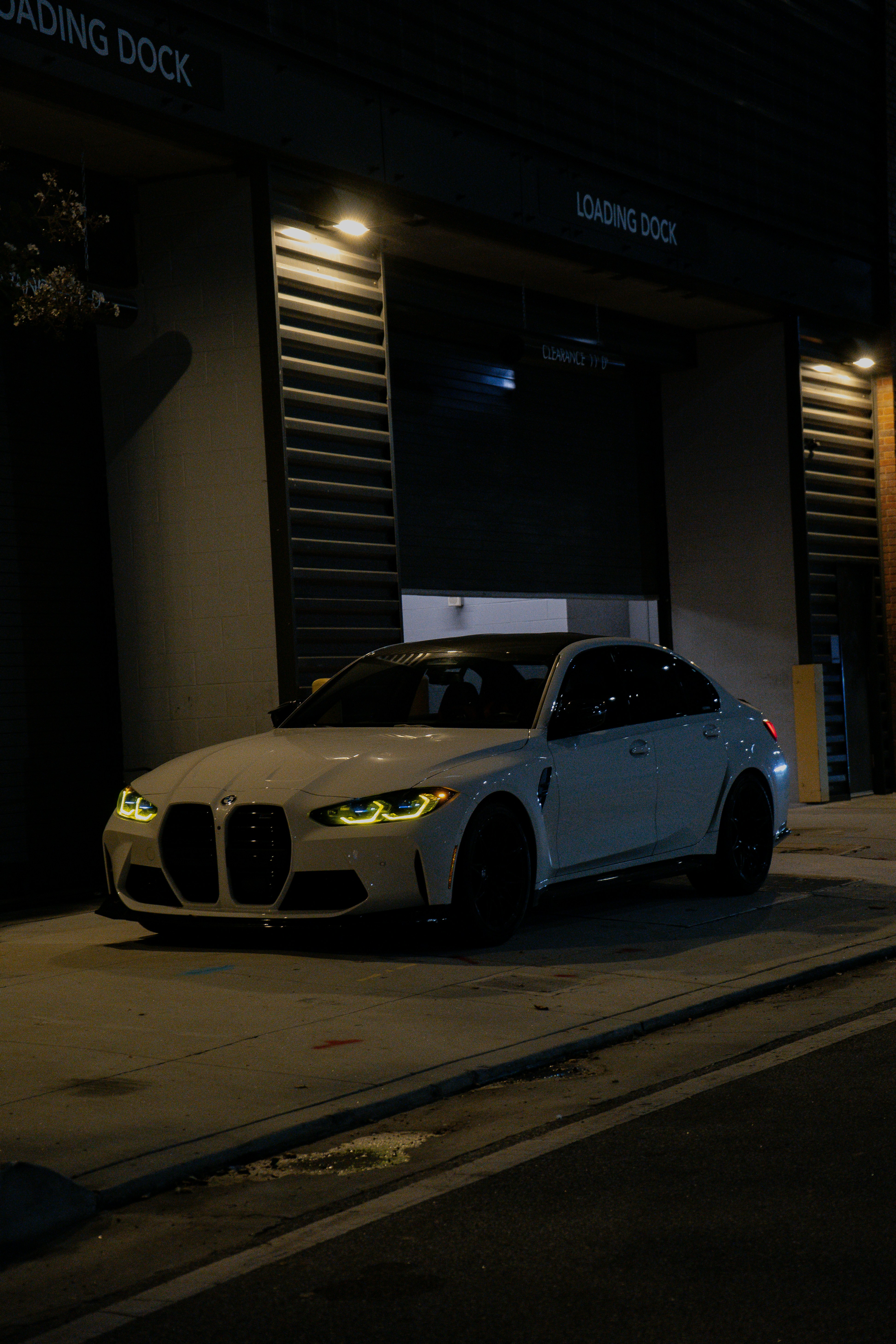 Midnight Inferno: White BMW Stalwart Pose under Loading Dock Lights