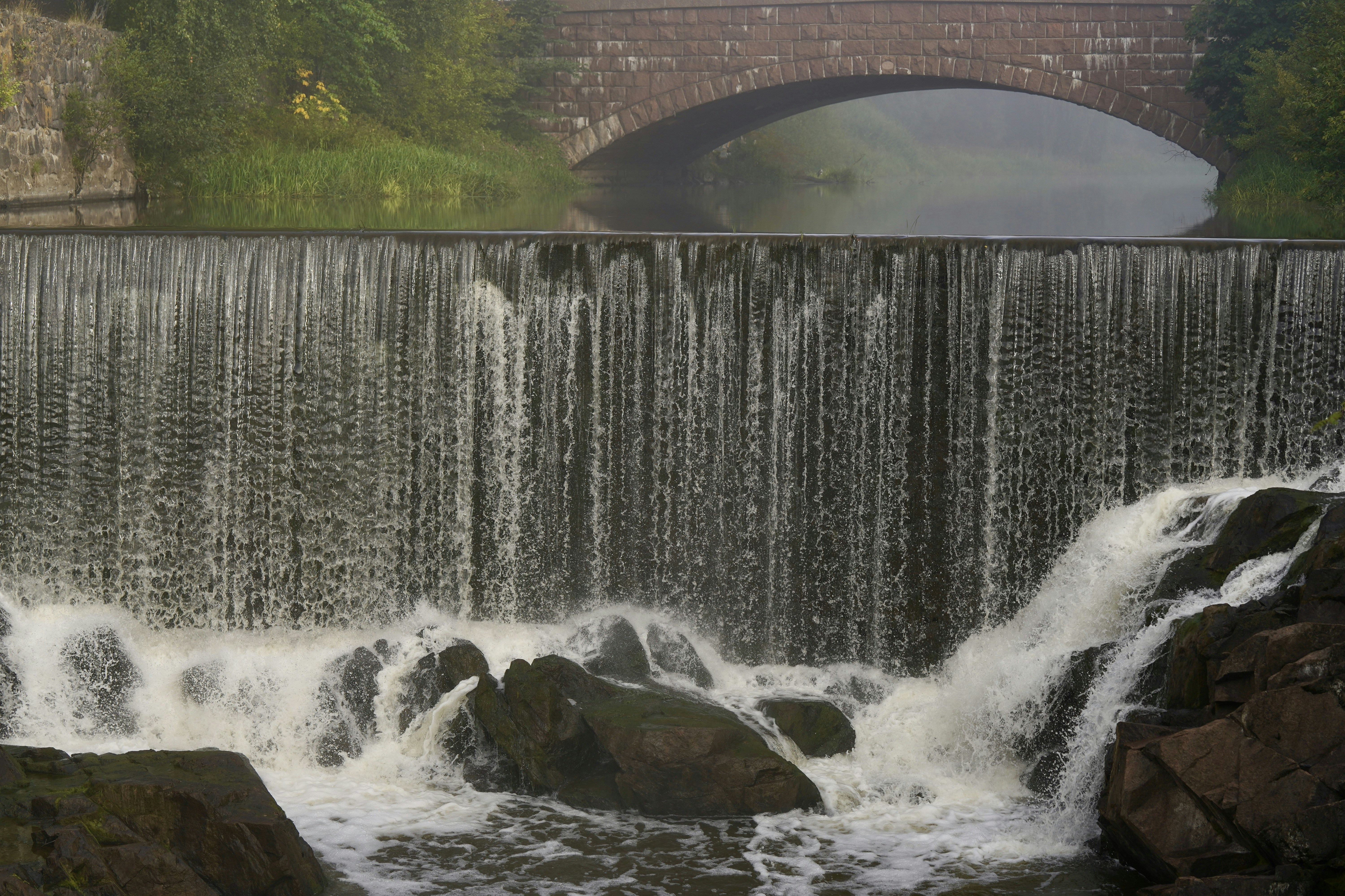 Flowing Curtain: Waterfall Overlook Beneath a Stone Bridge