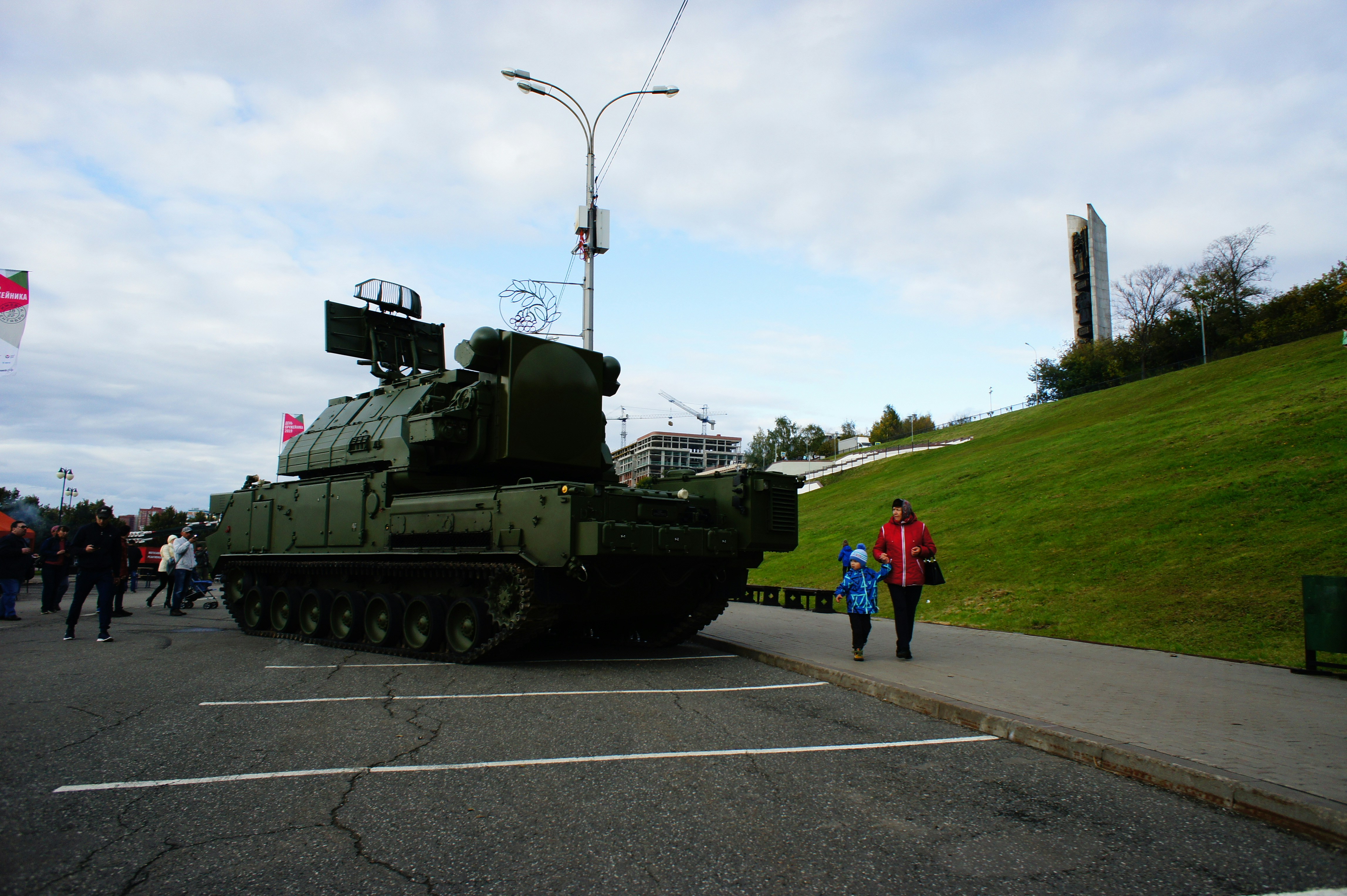 Green Military Vehicle on a City Street with Onlookers