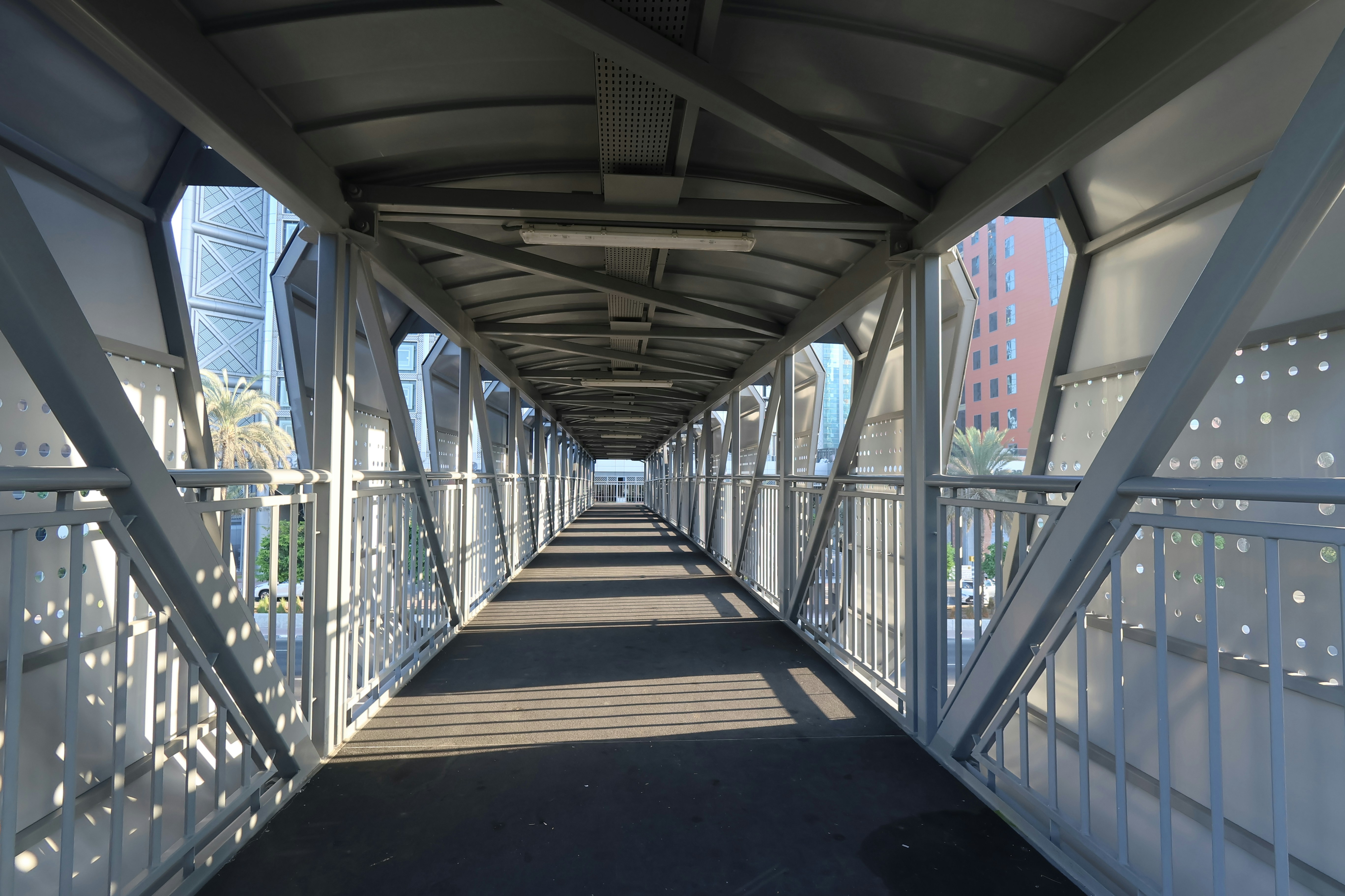 A covered pedestrian bridge with metal railings and perforated side panels