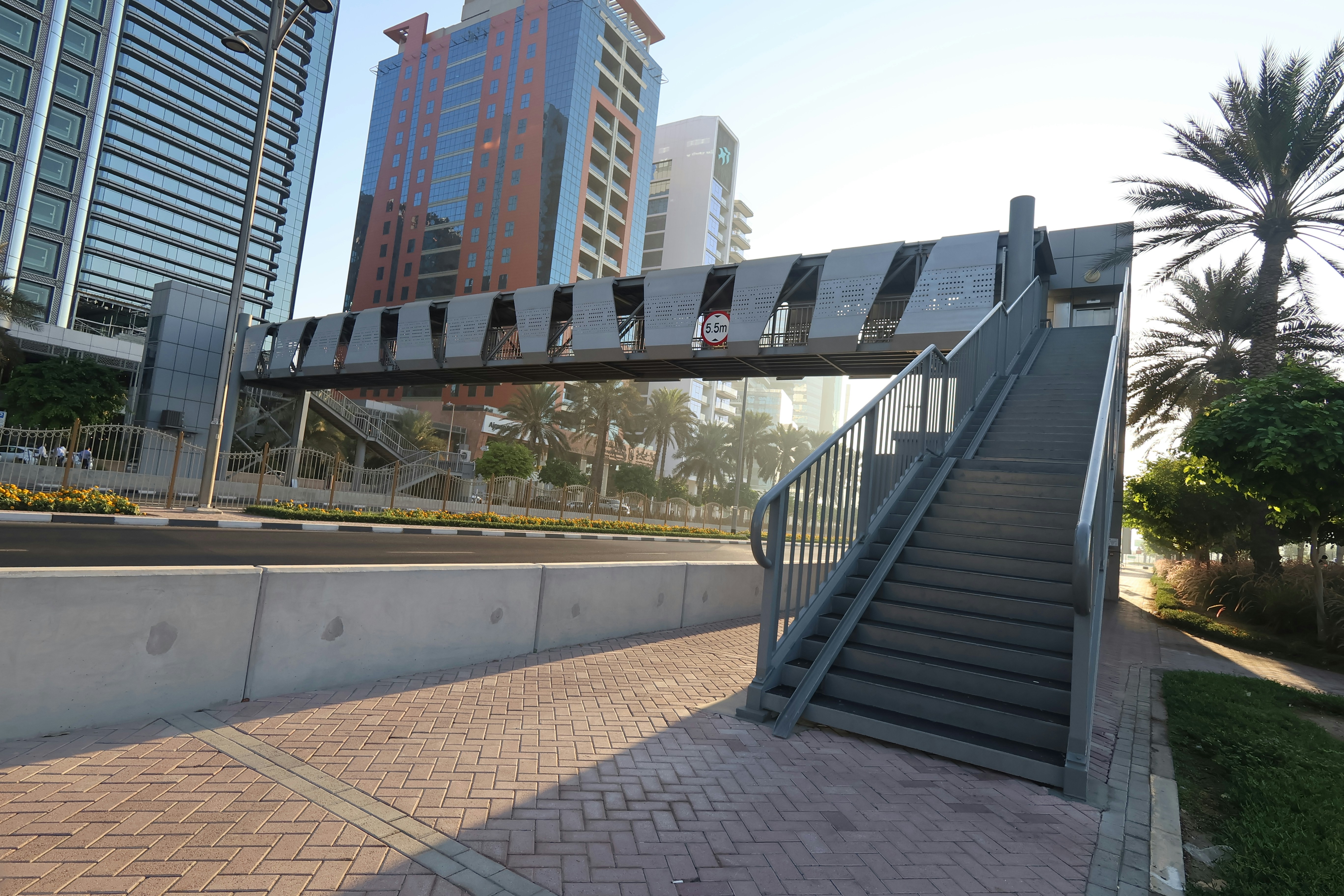 A modern pedestrian bridge with metal stairs over a road in a city
