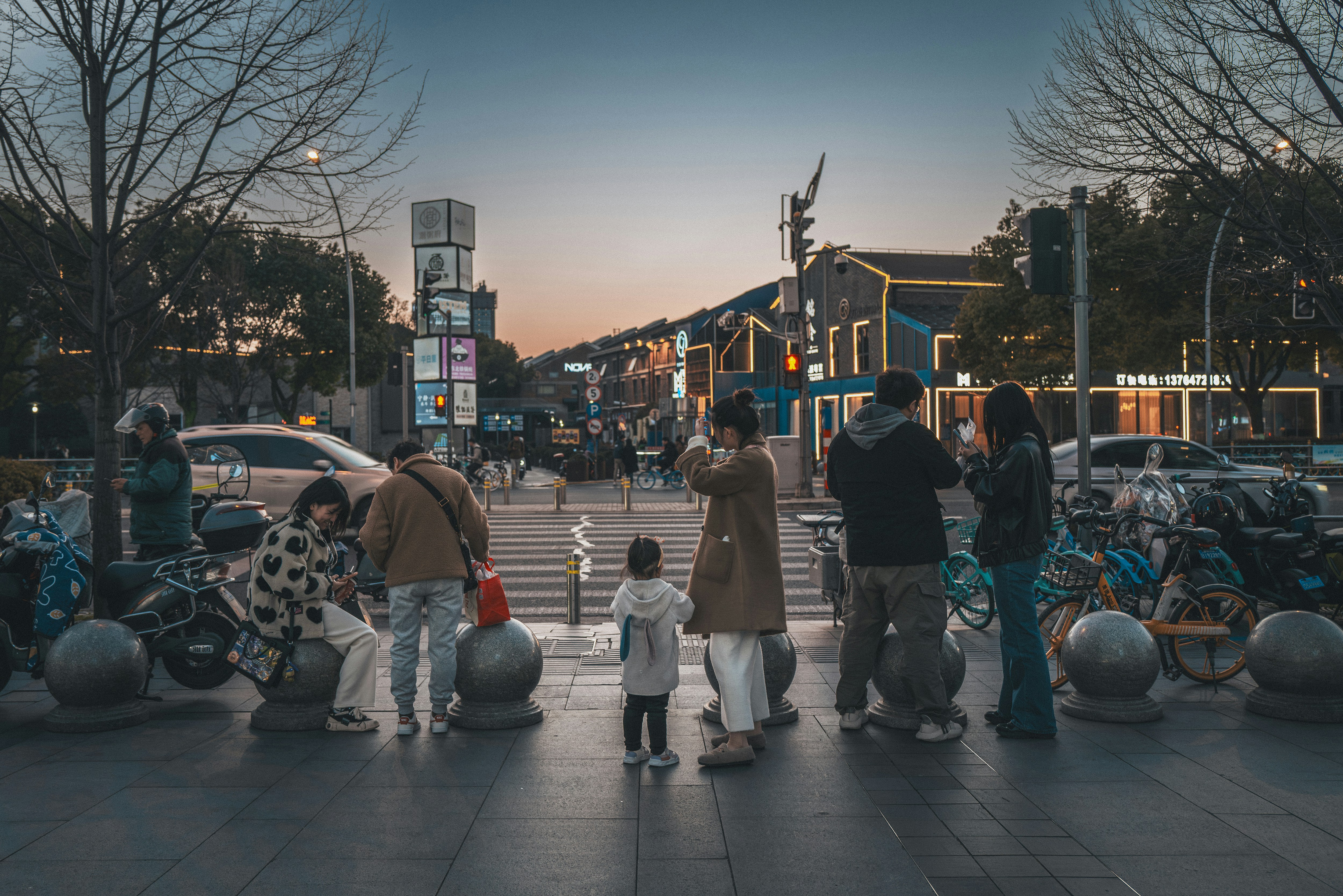 Crossing at Dusk: A Family Moment in a Busy Pedestrian Street