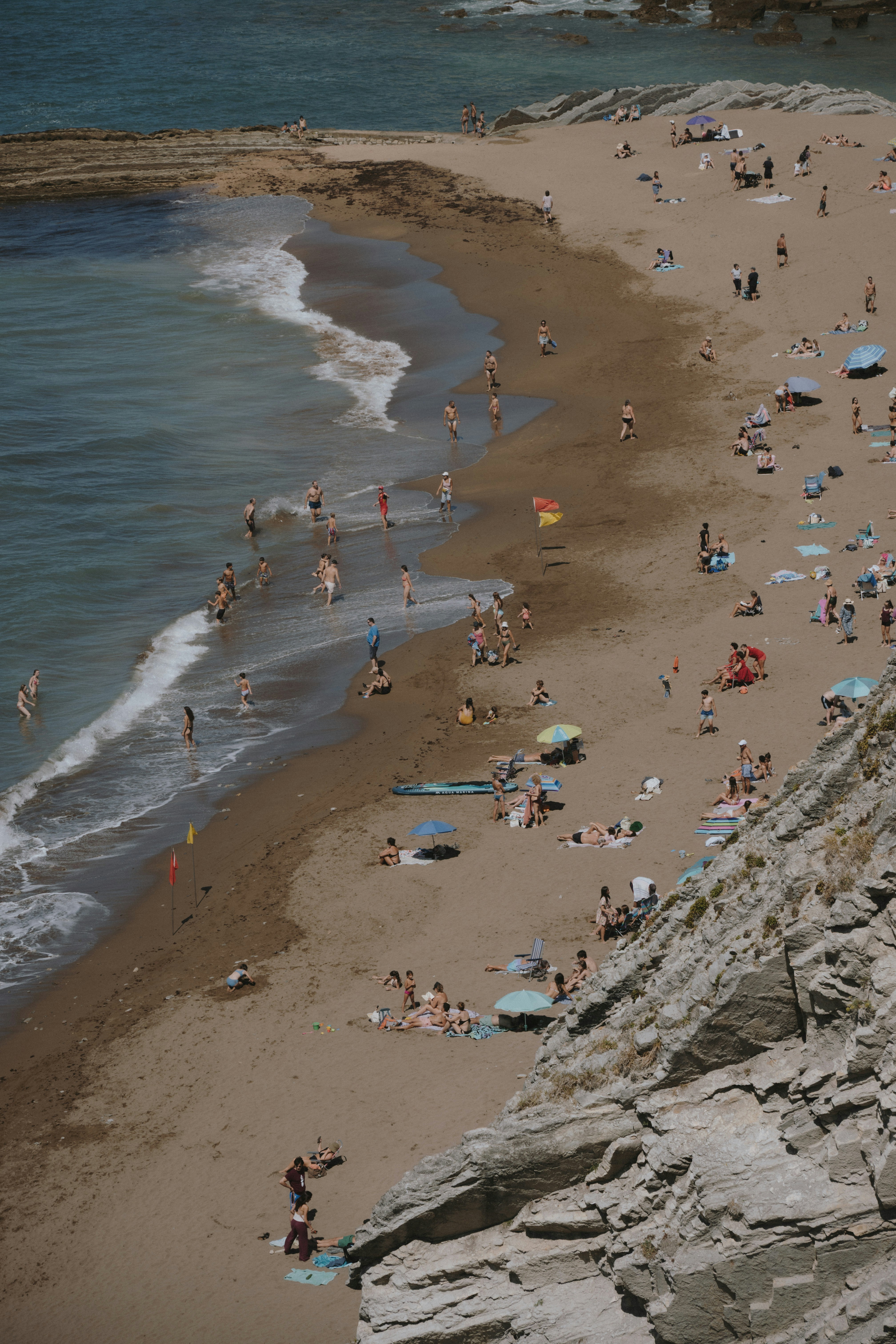 Sunlit Strand: A Busy Coastal Tapestry of Beachgoers and Waves