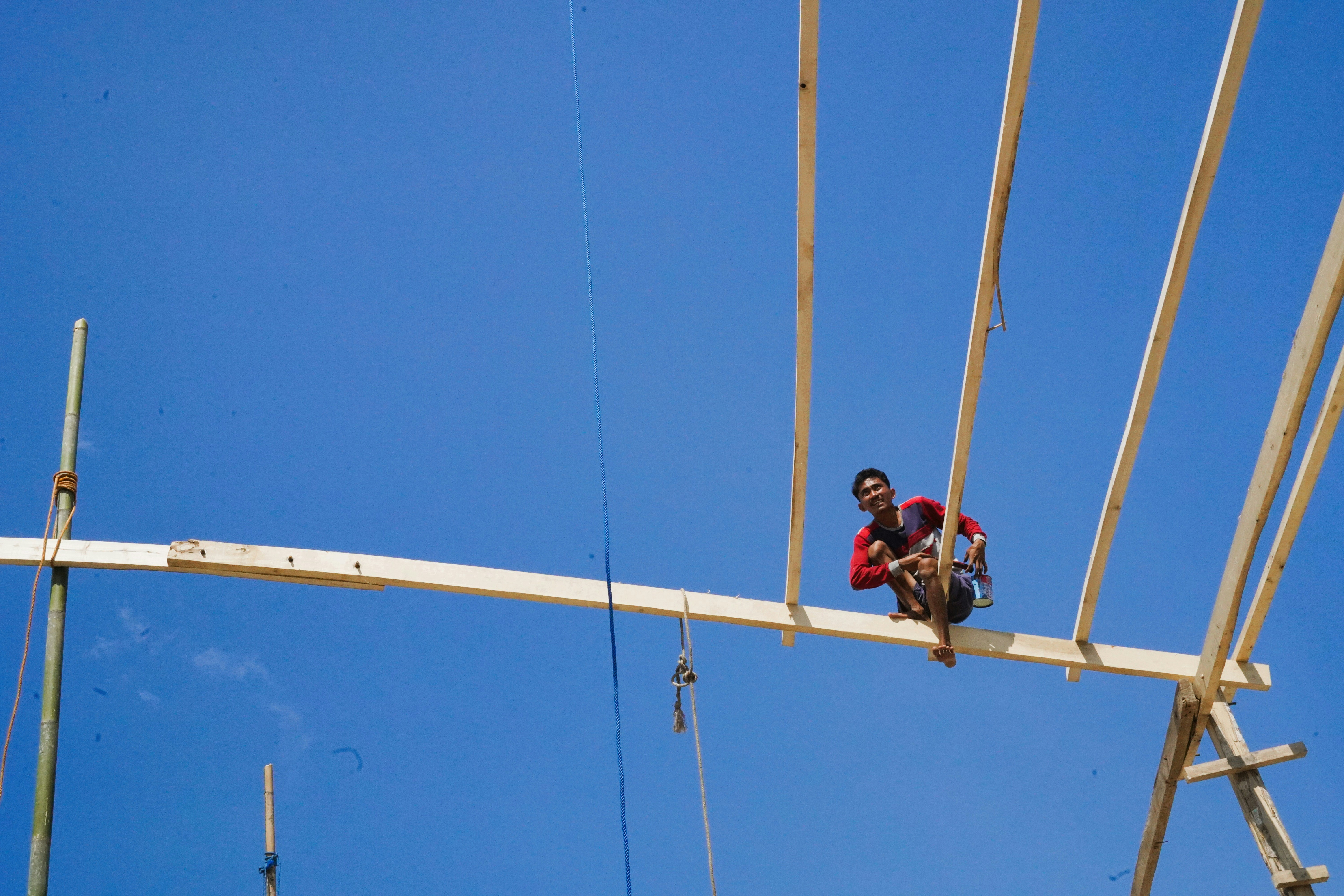 Riser Above the Blue: Builder on a Timber Truss Under Construction