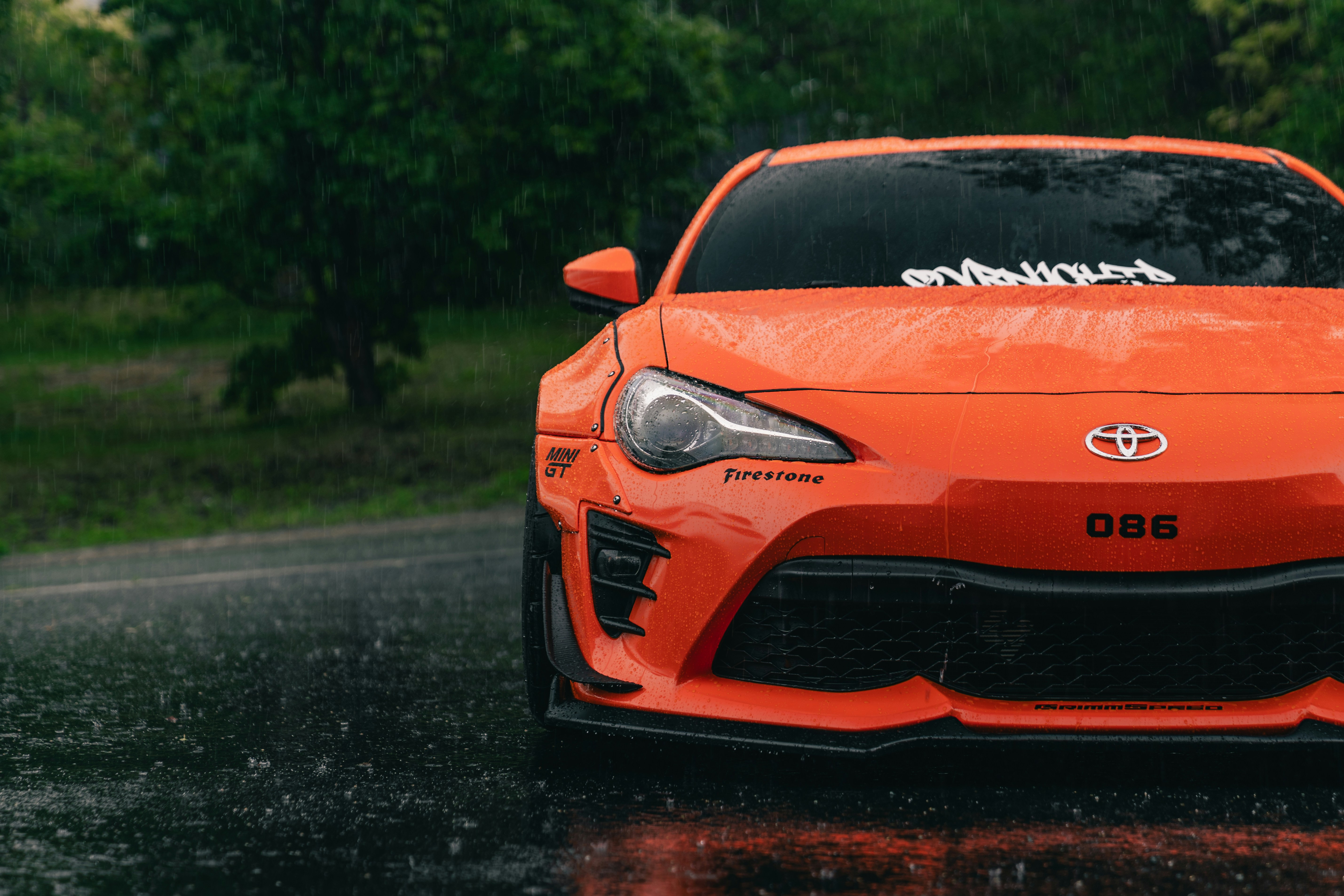 Orange Racer Emerges from Rainy Wake