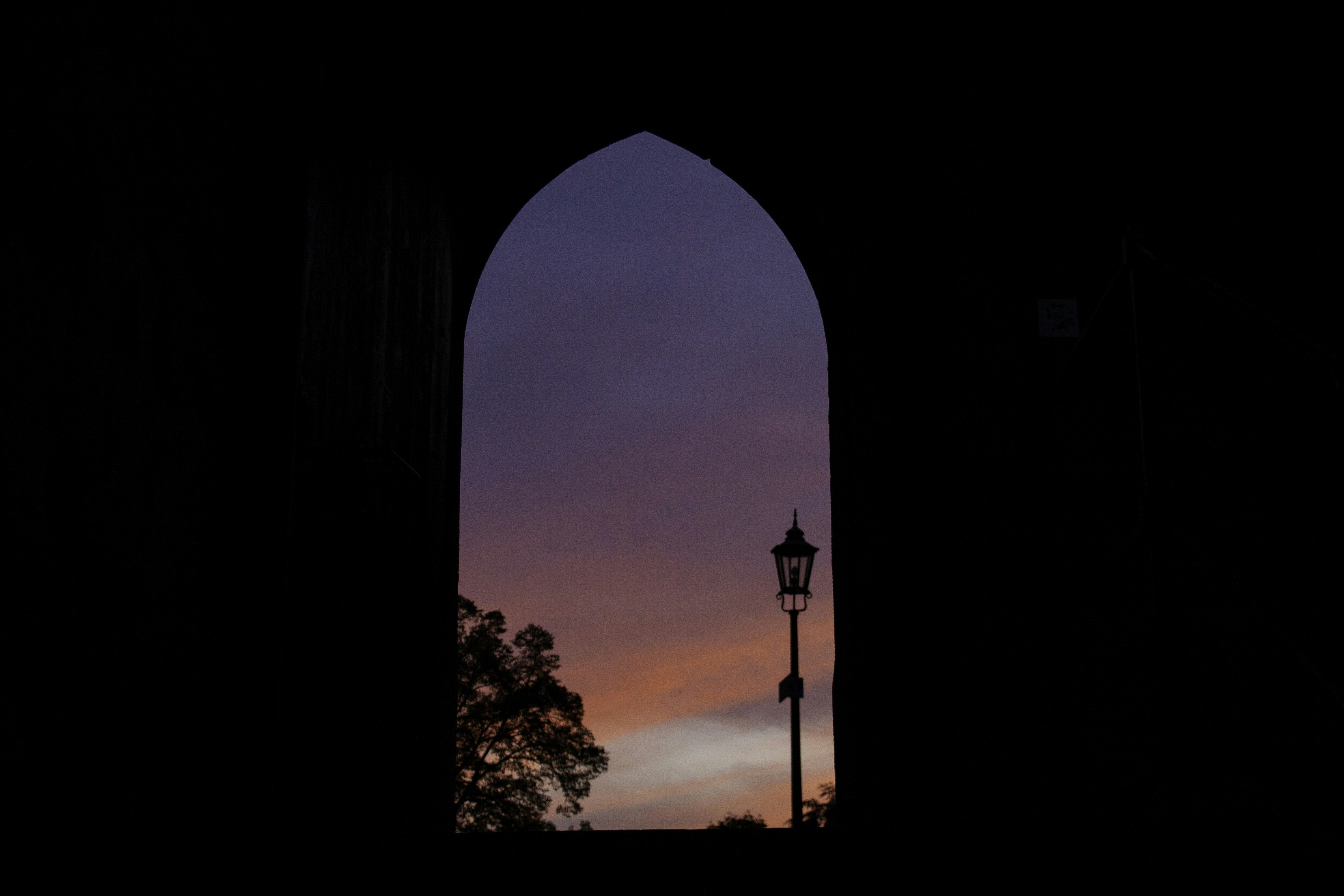 Silhouetted Archway Framing a Tulip Sunset Street Lamp