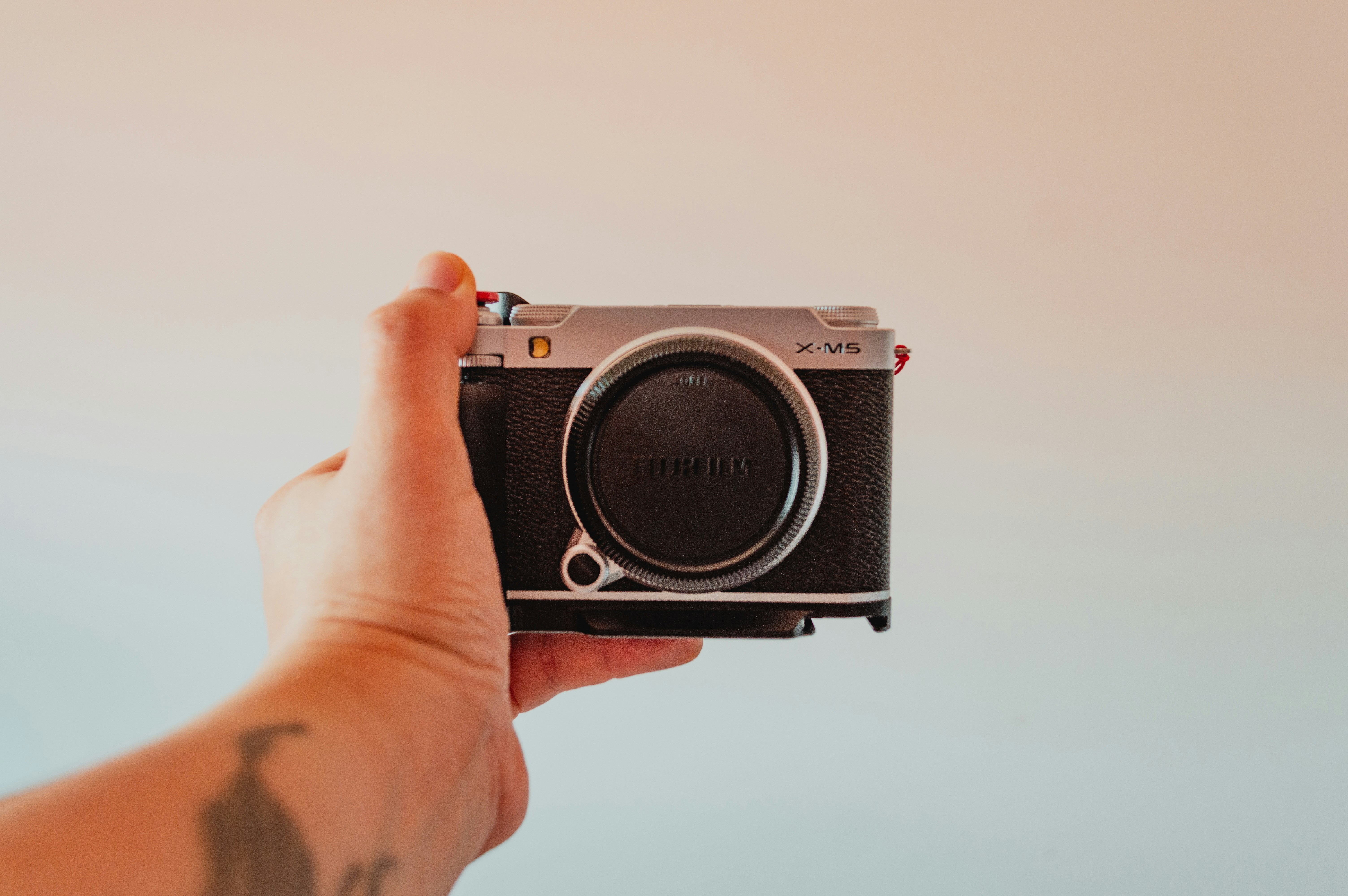 Minimalist Moment: a hand-held camera toward a vintage rangefinder against a pastel horizon