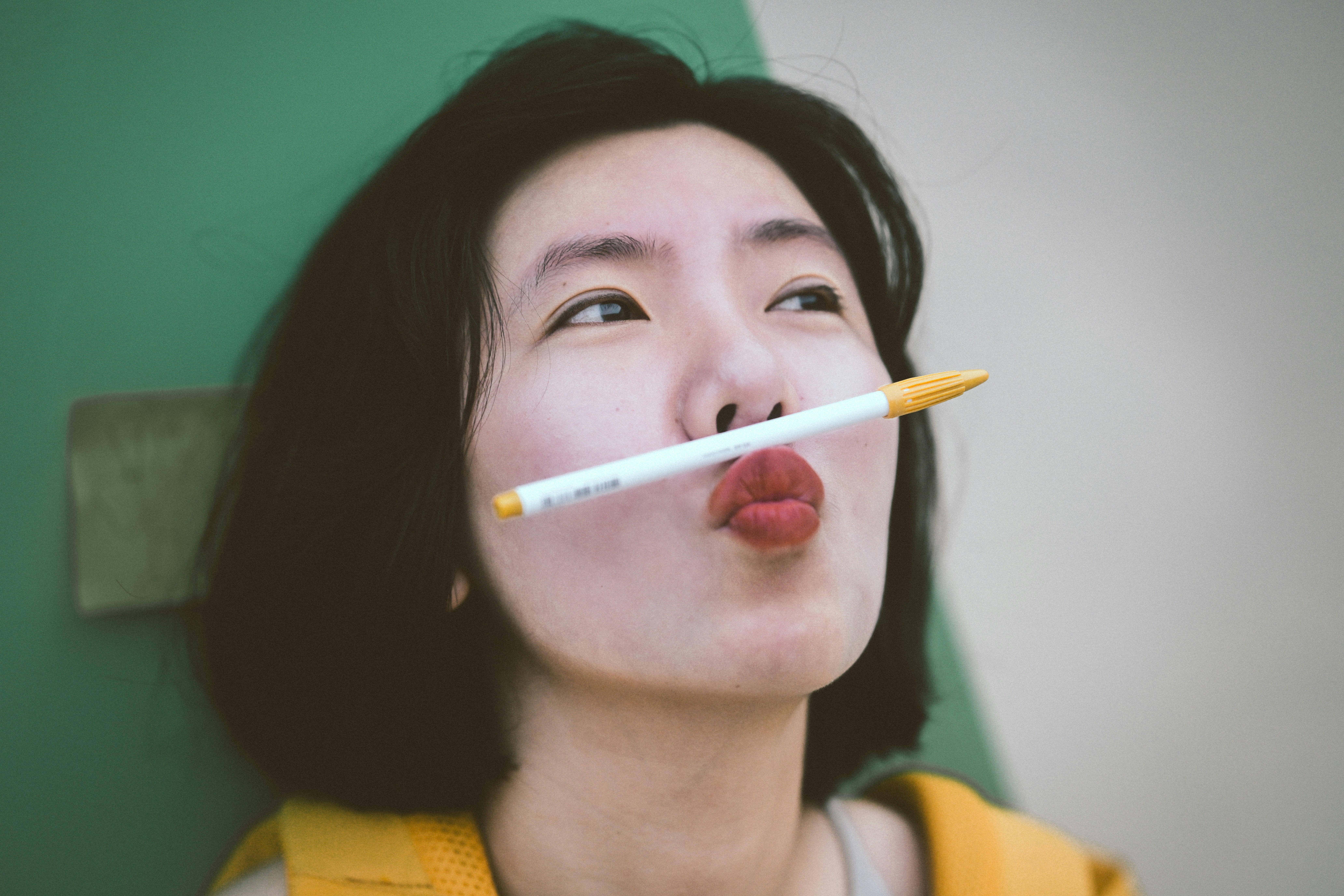 Pencil-streaked Portrait: Whimsical Gaze with a Pen Bonded Between Cheek and Smile