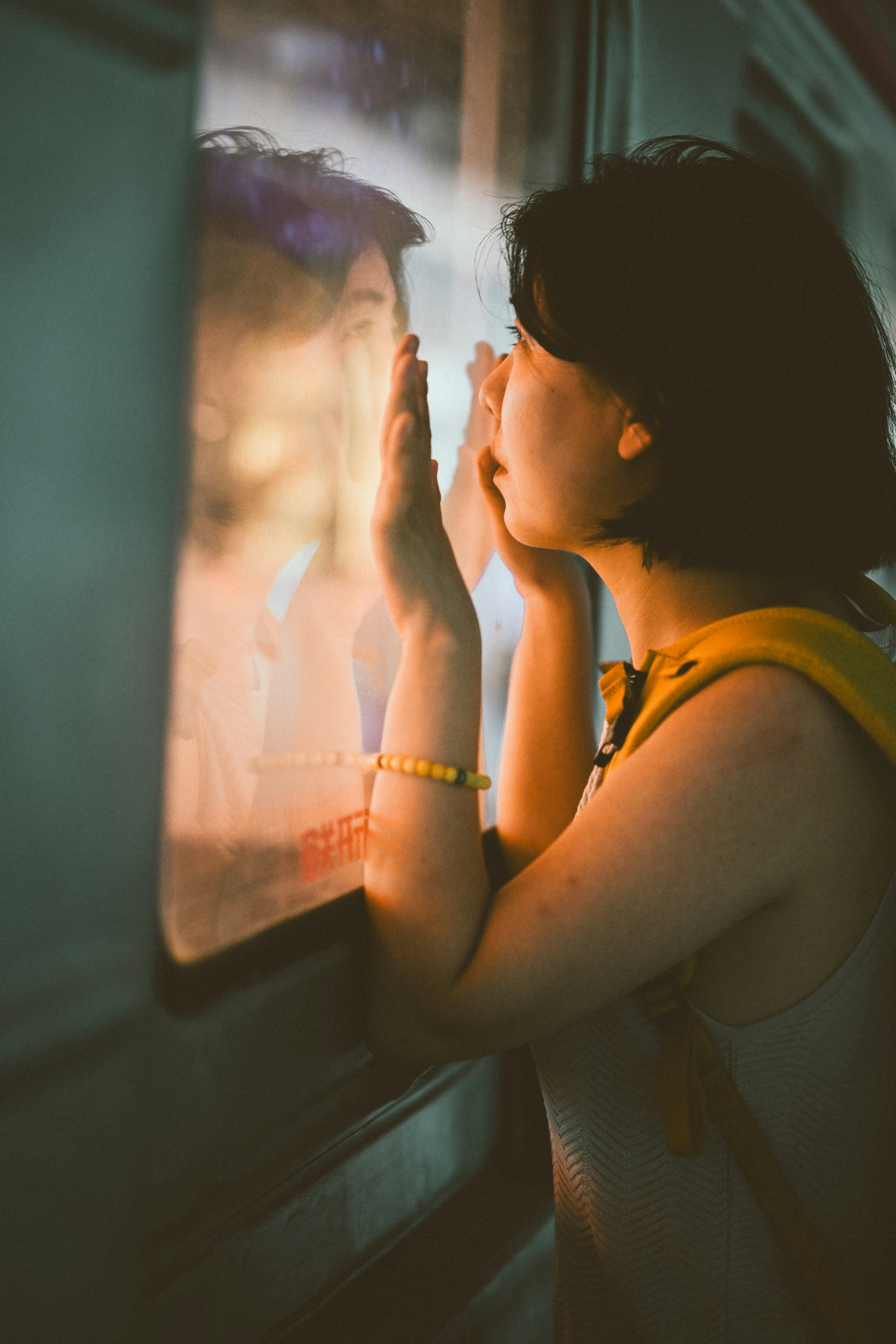 A woman pressing her hands against a train window in warm light