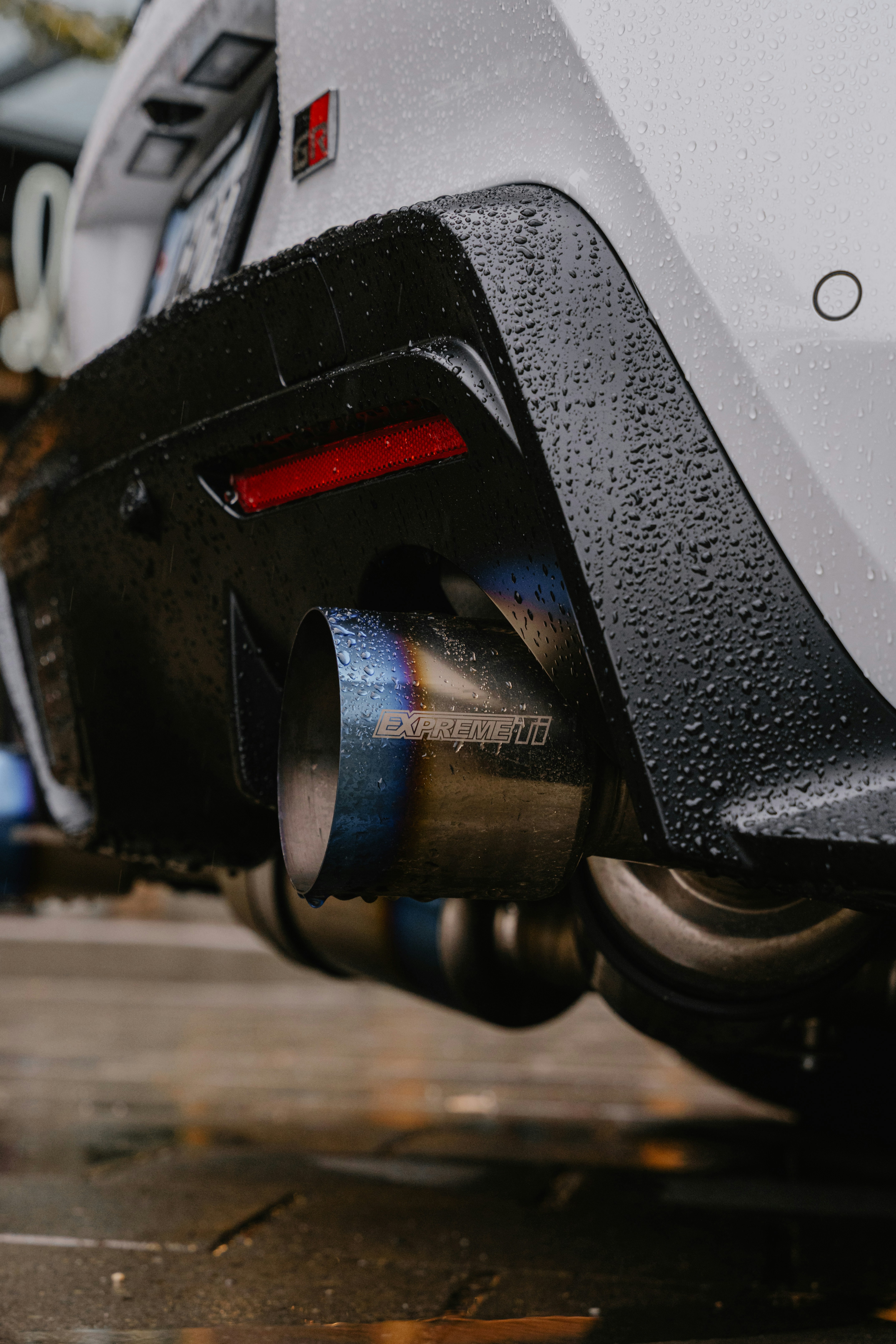 Industrial steam and chrome: close-up of a sports exhaust after rain