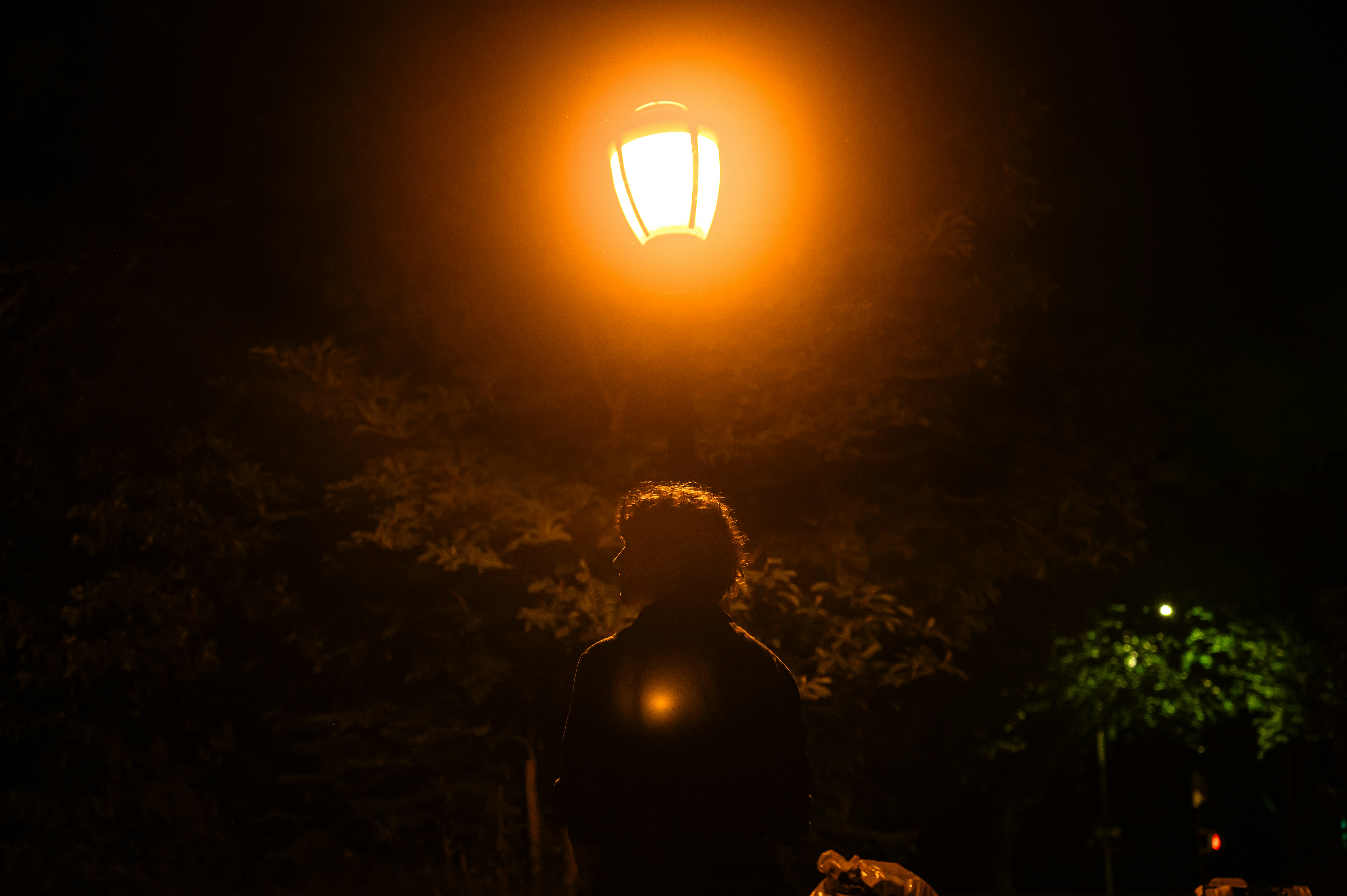 Night Lantern Reverie: A Silhouetted Figure Beneath a Glowing Street Lamp