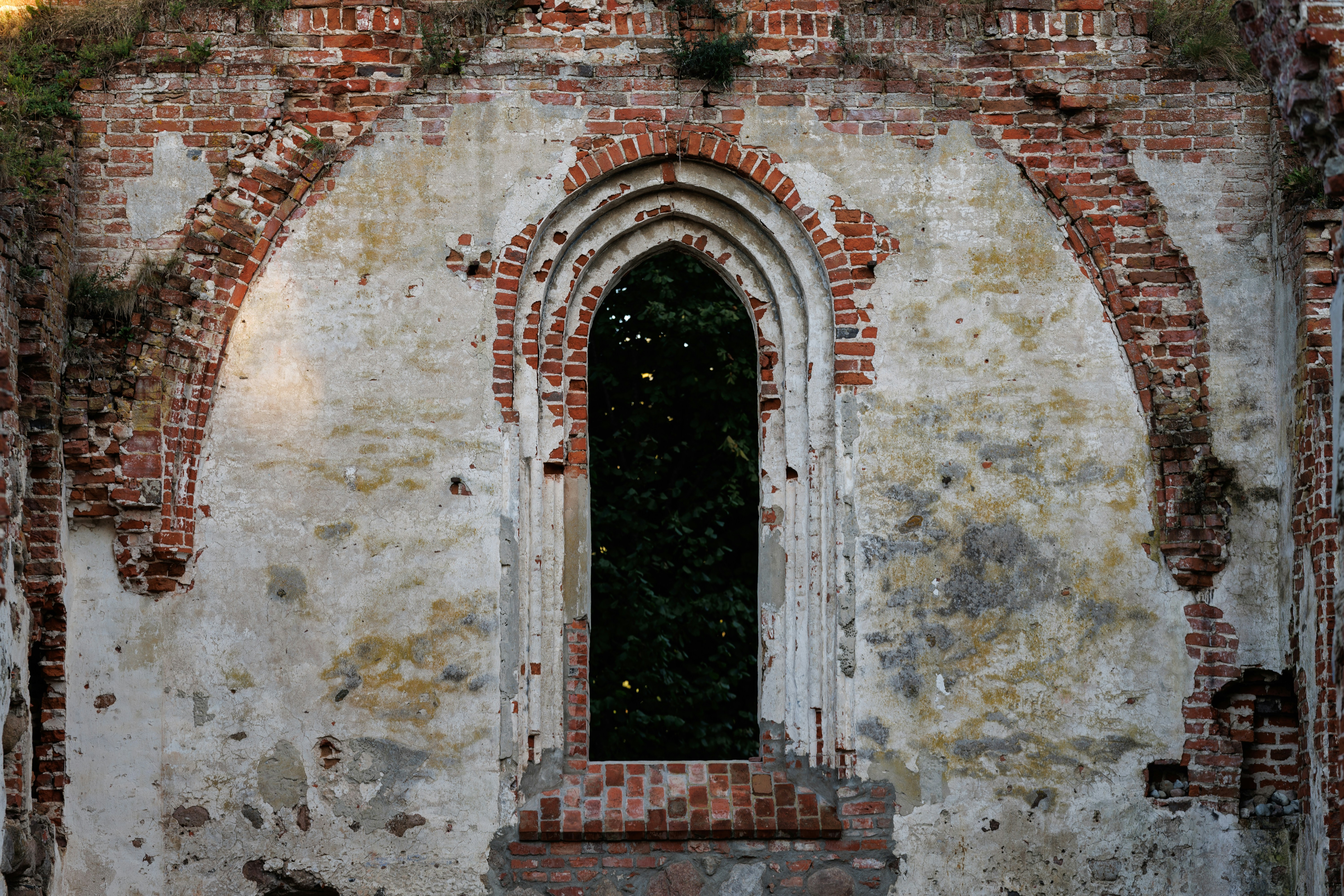 Ruined Archway Framing a Dark Green Forest Within