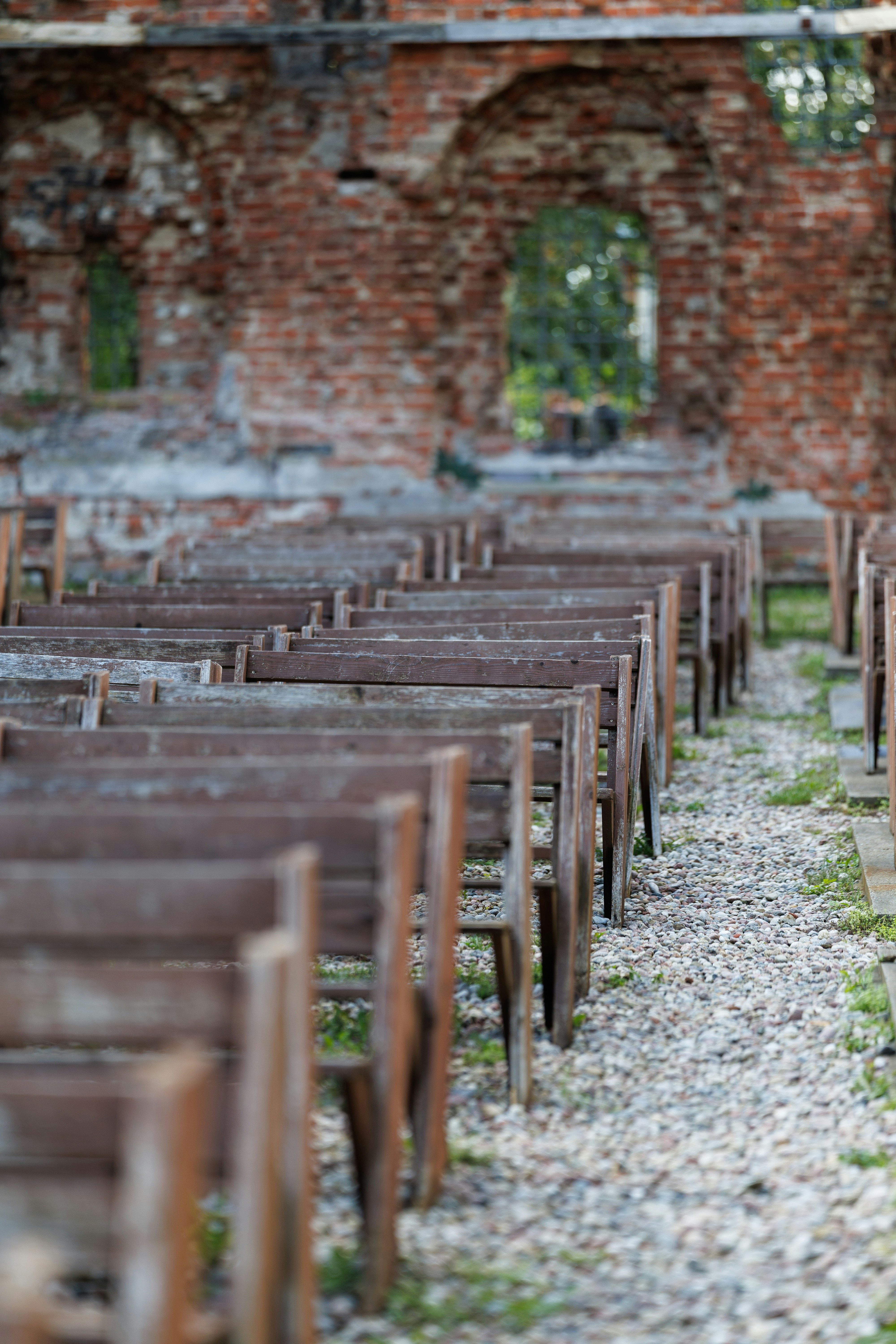 Rust and Repetition: Abandoned Pews Against a Crumbling Brick Arch
