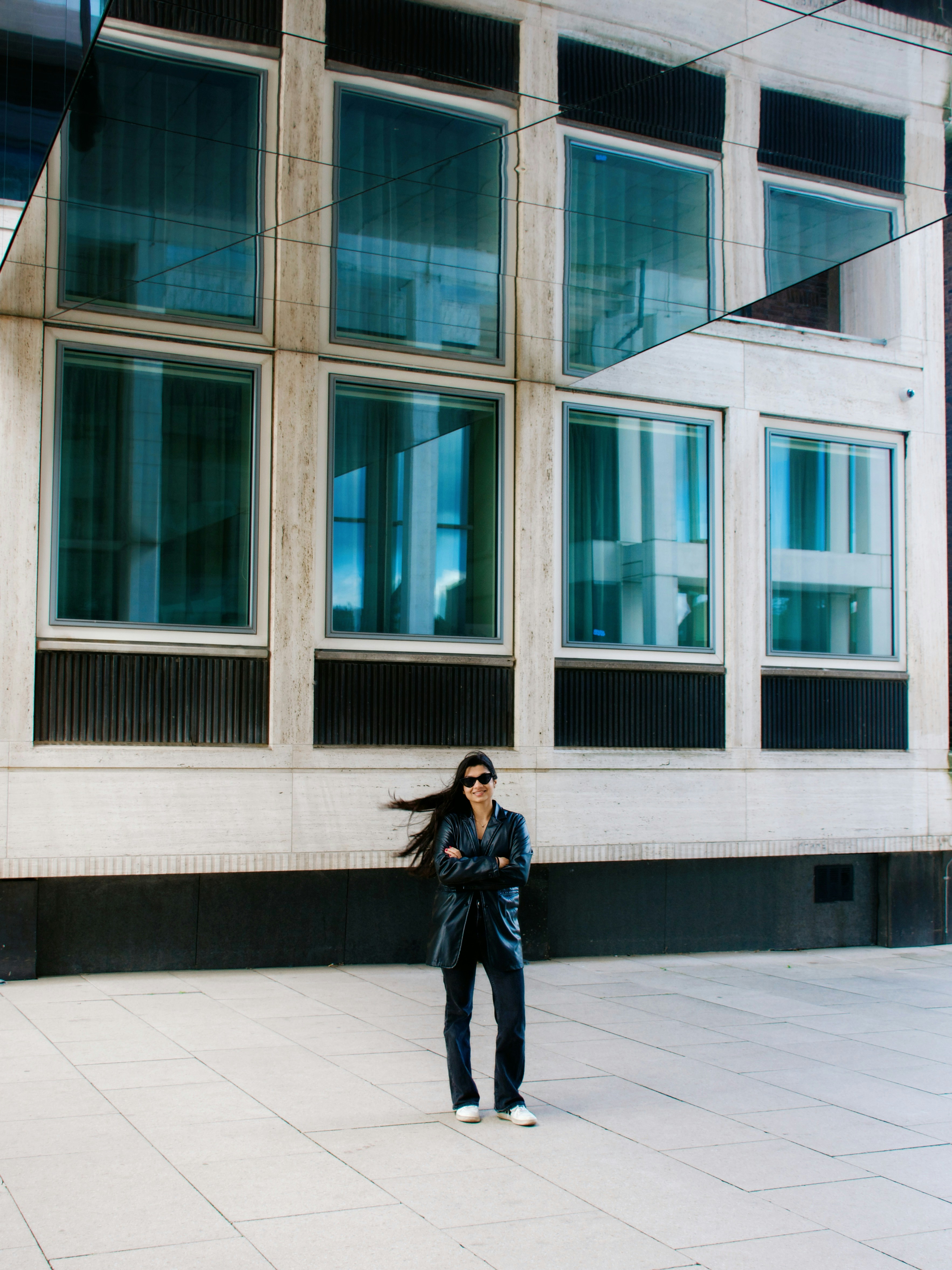 Urban Quiet: Woman in Leather Standstill Before Brutalist Glass