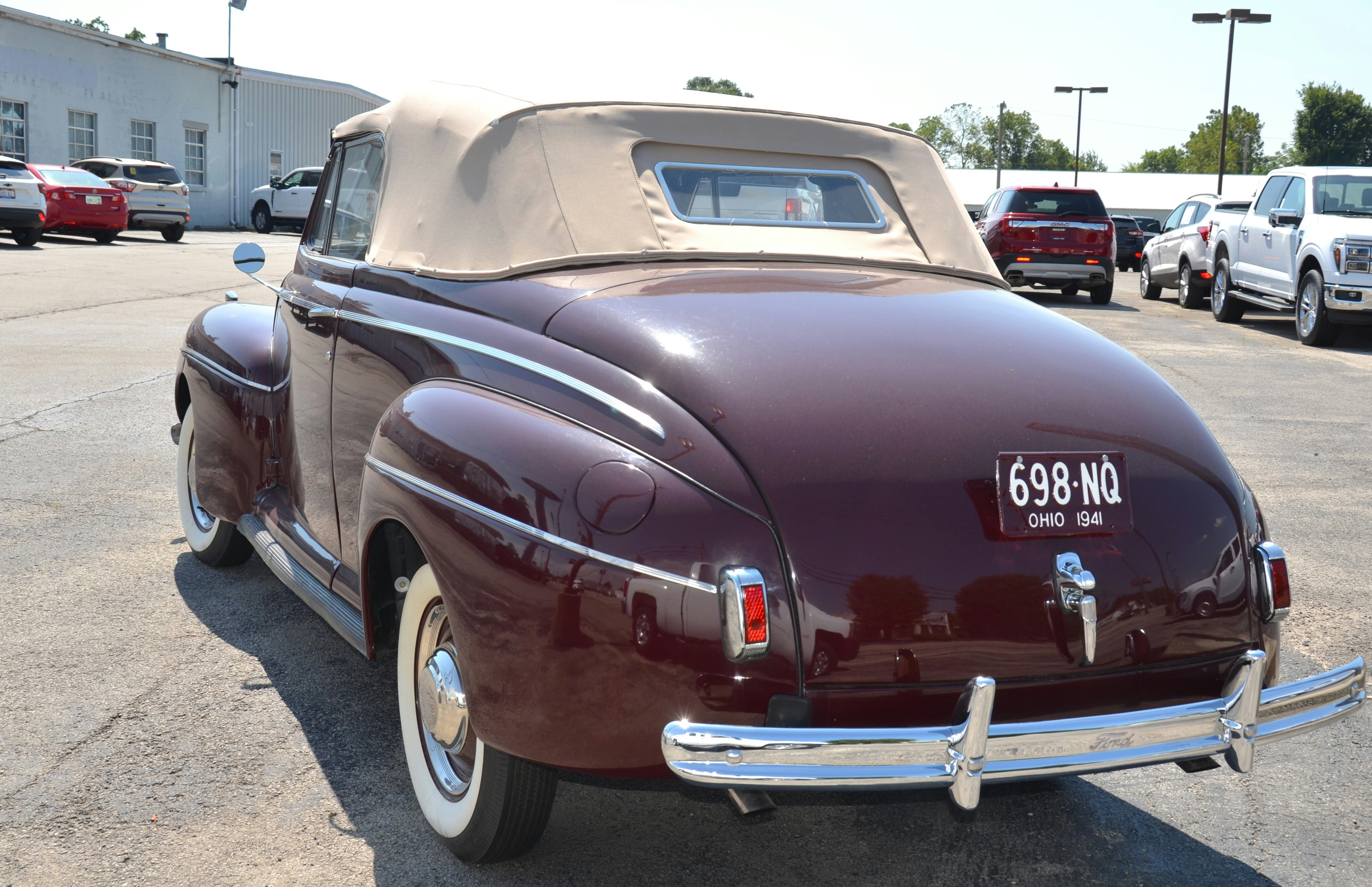 Mid-Century Maroon Convertible: Chrome Accents and Soft Top in a Car Lot