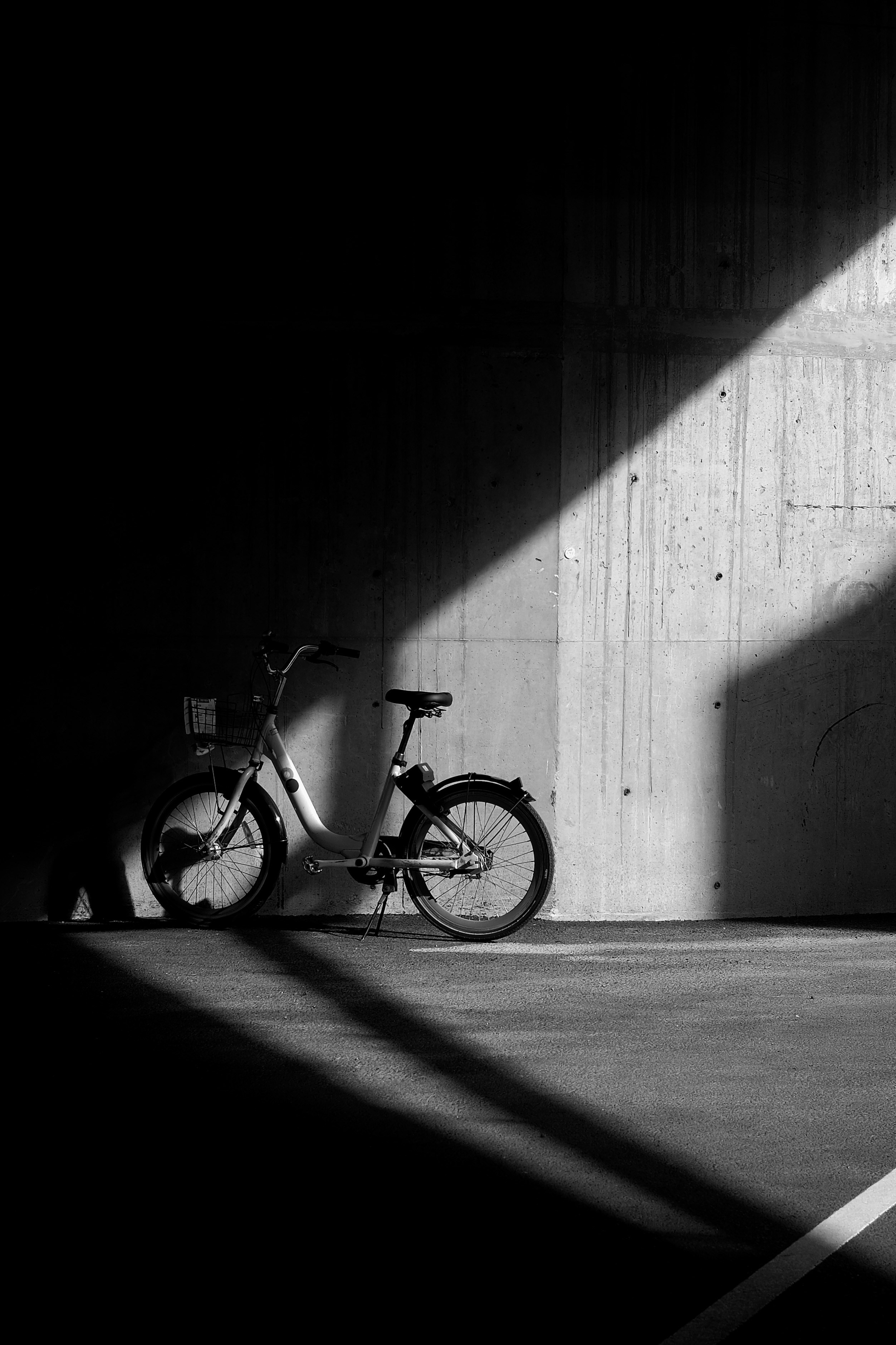 Shadowed Ride: A lone folding bike tucked in diagonal light