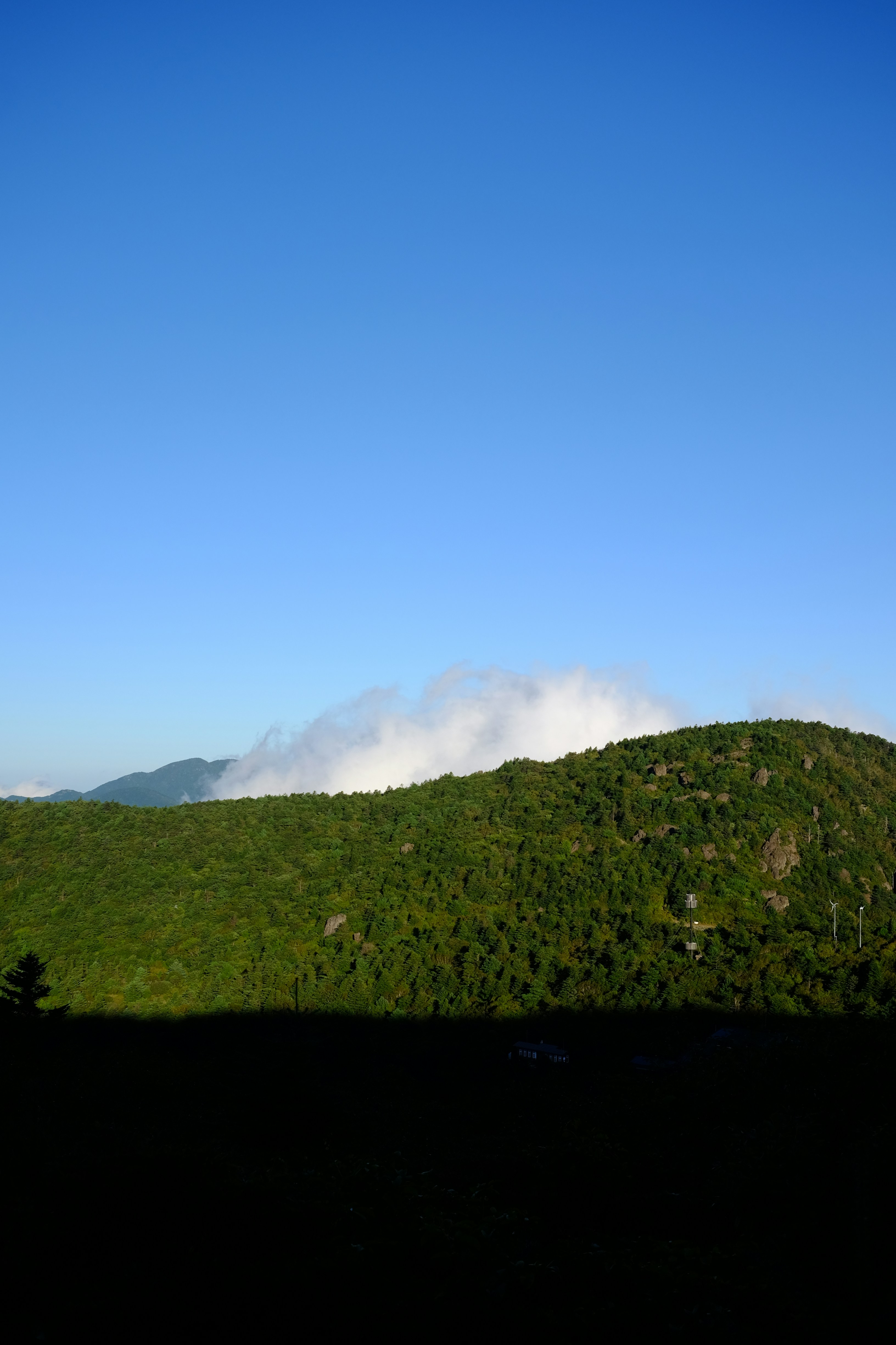 Azure Sky Over Green Slopes with Shadowed Foreground