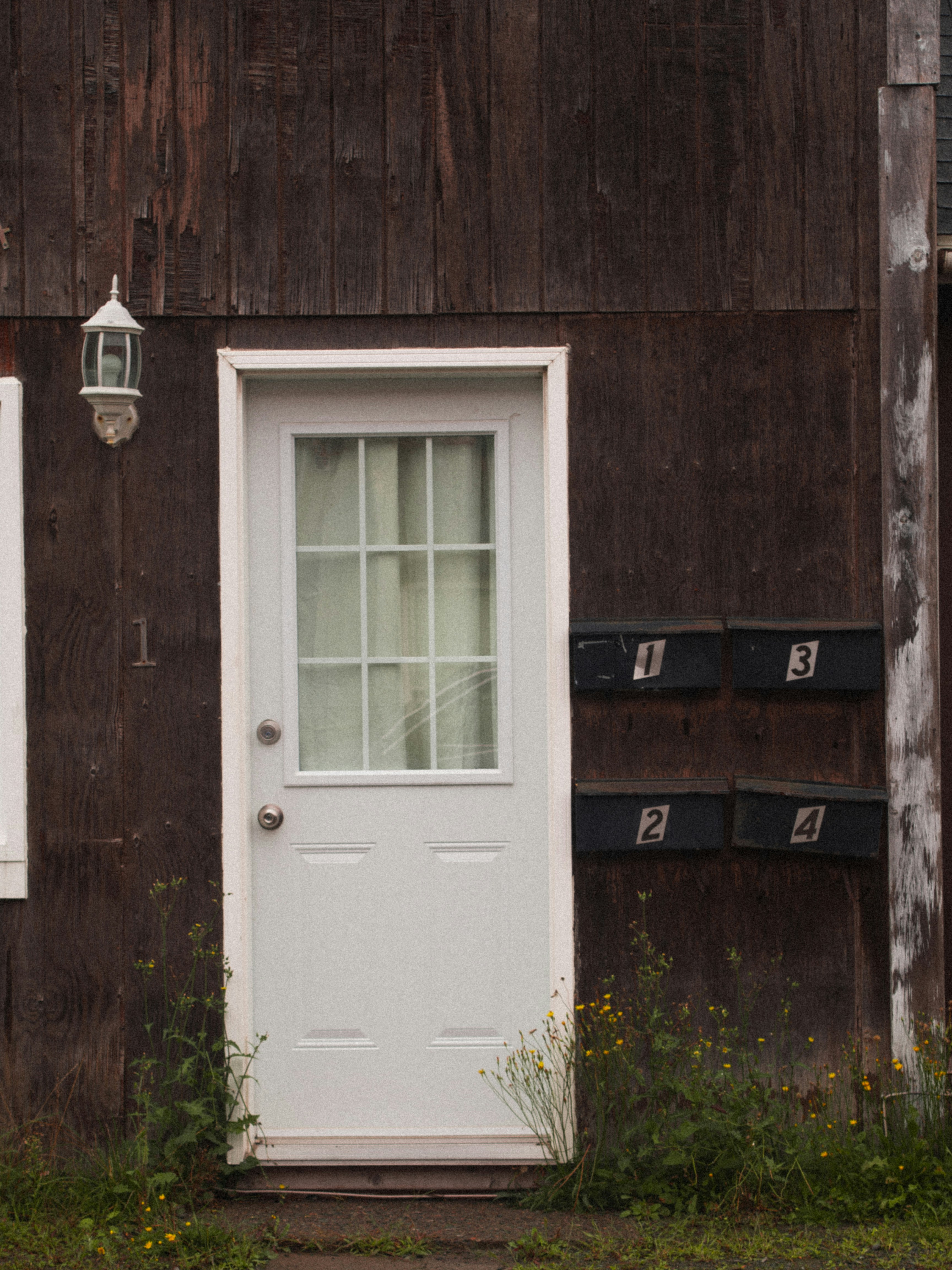 White door in weathered barn with scattered mailboxes