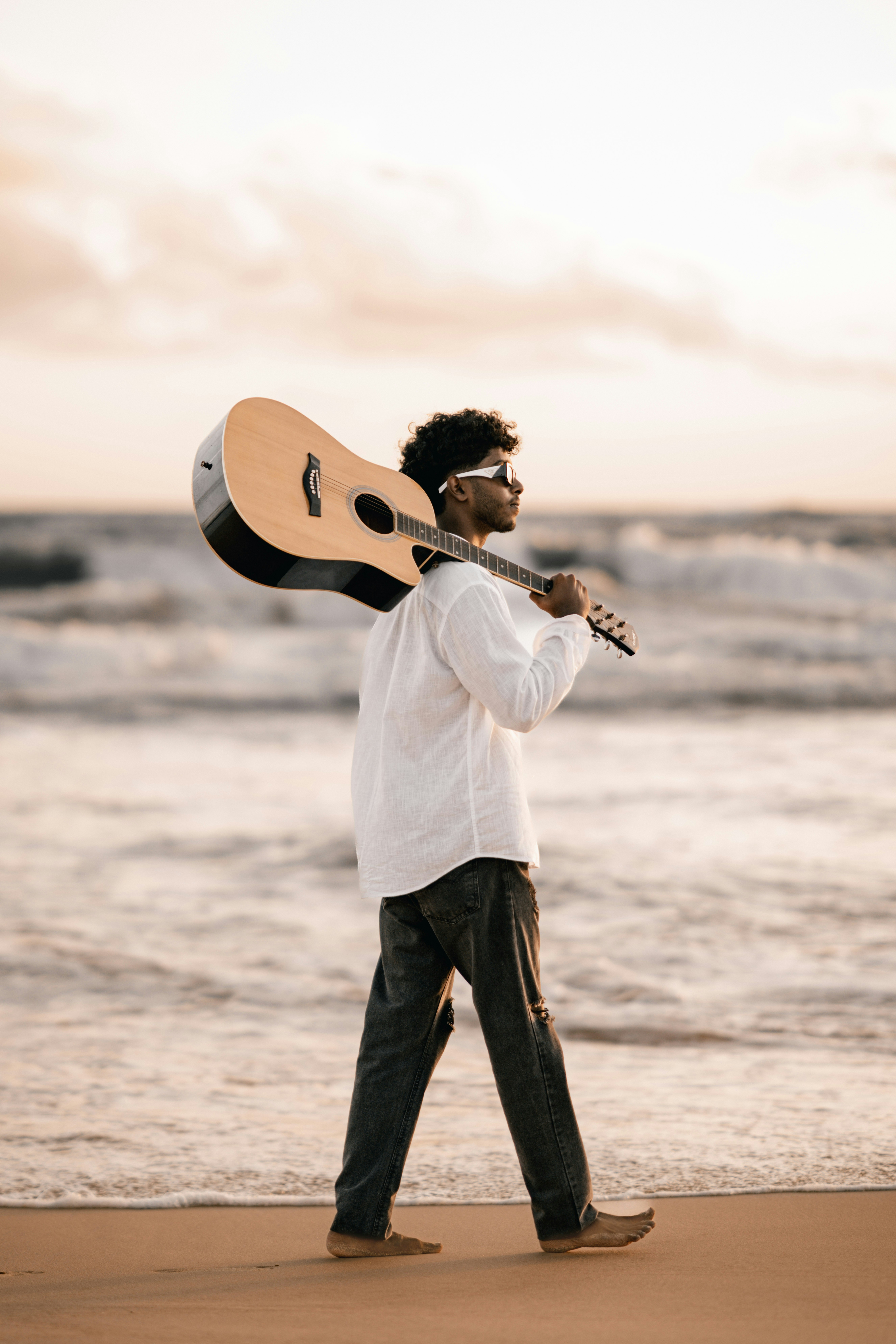Sunset Serenade: A Guitarist Walks the Quiet Shore