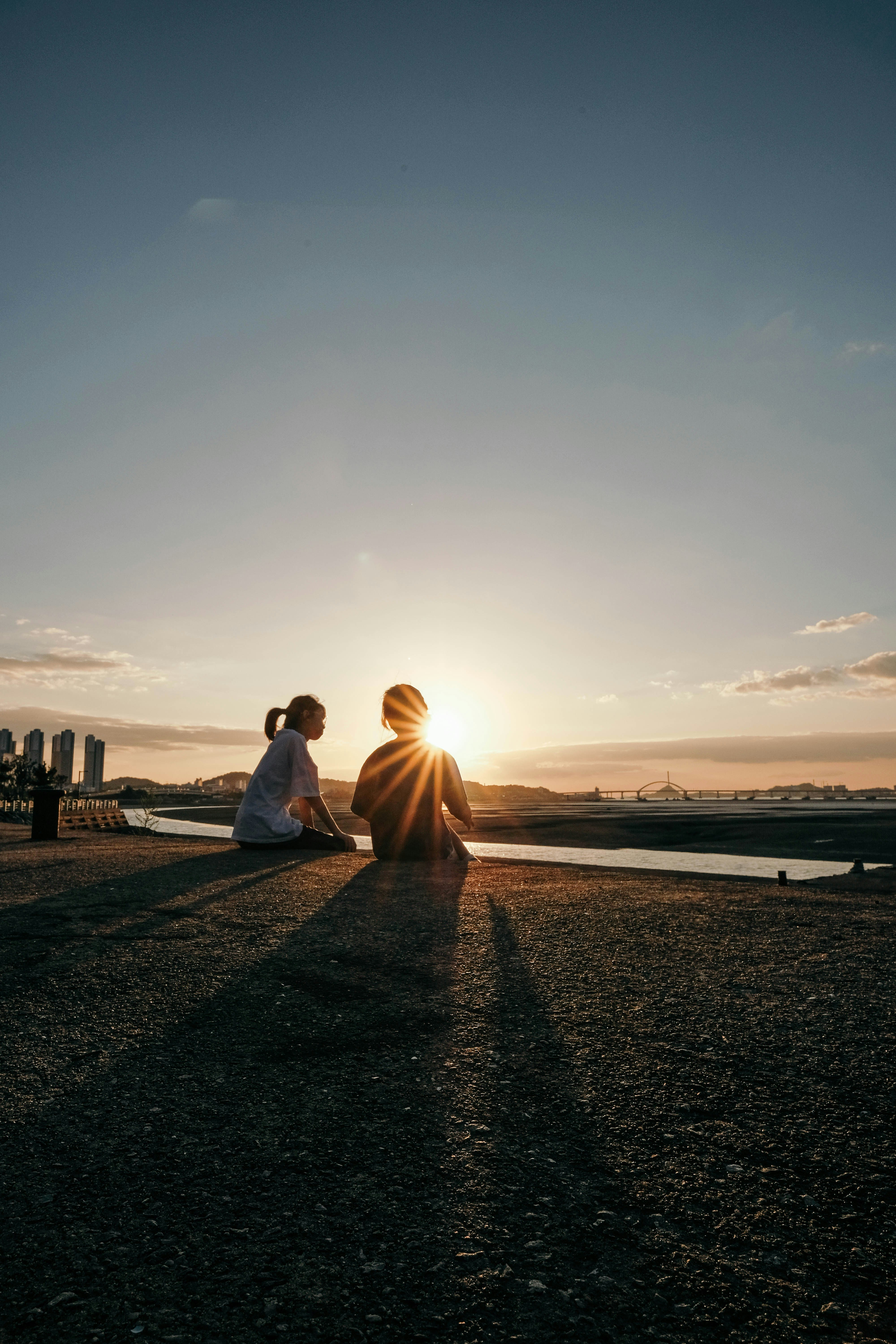 Sunlit Silence: Two Figures at Dusk on the Waterfront Edge