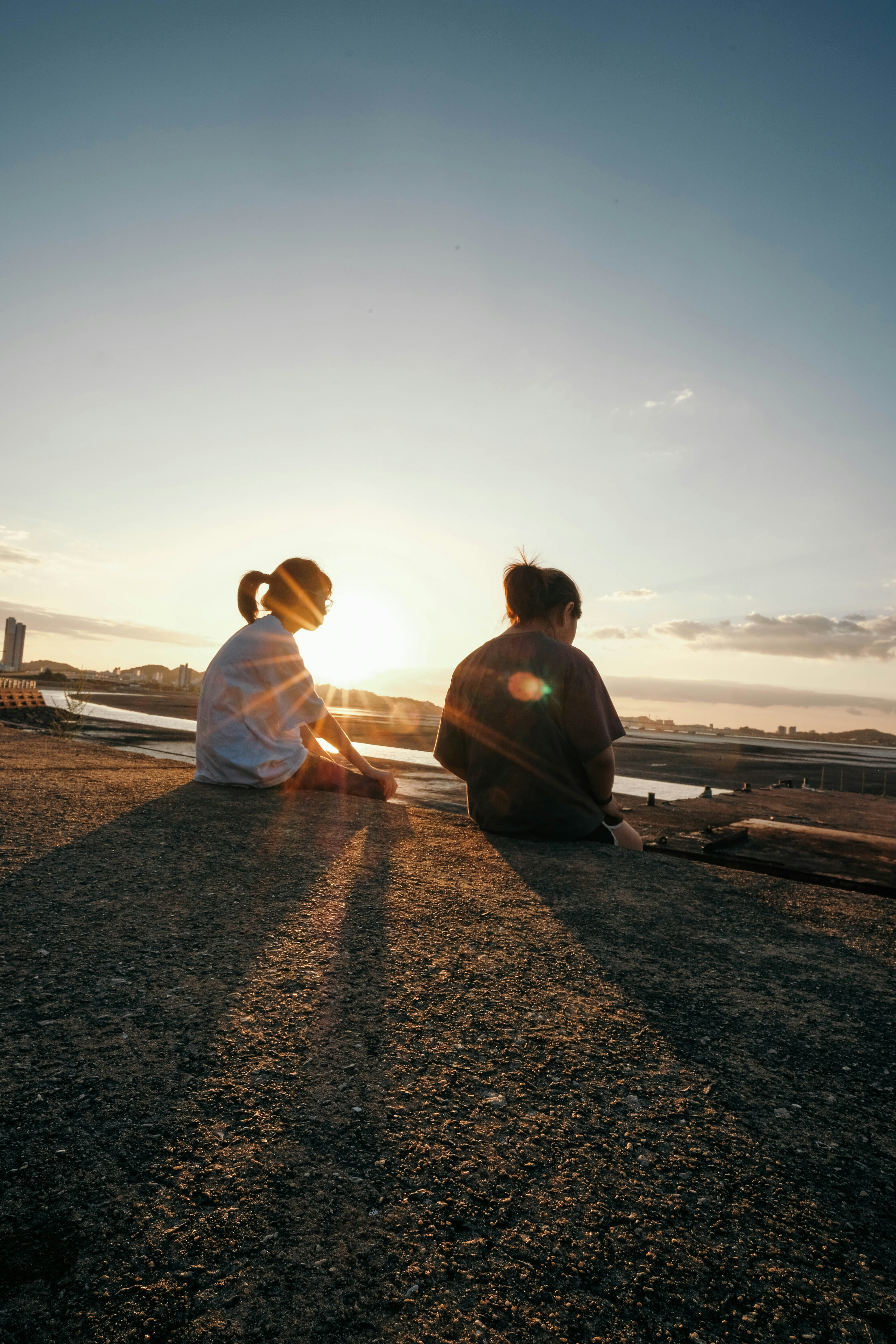 Two Voices in Sunset: Friends Seated on Rooftop Edge
